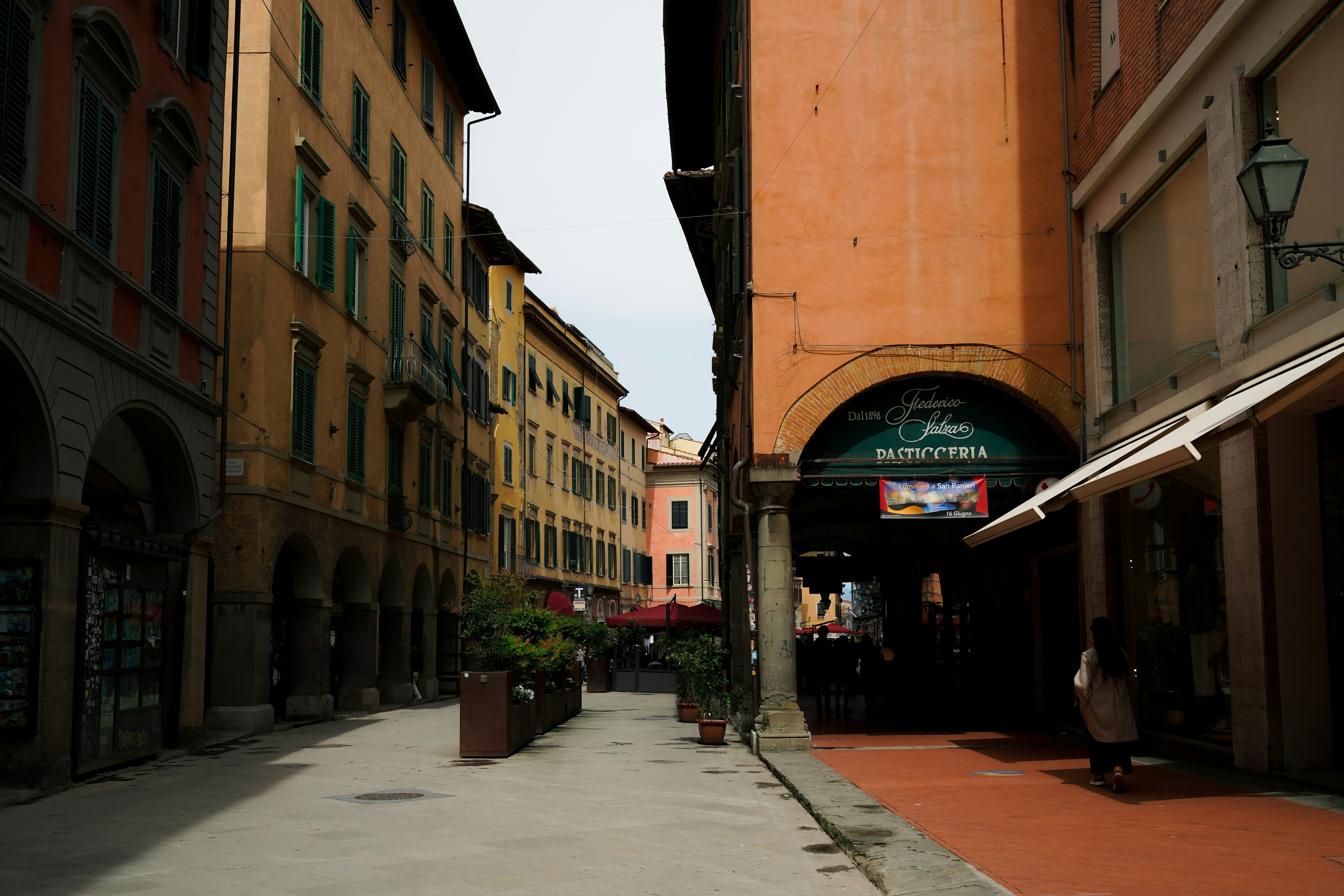 Sunlit Calle of Colors: A European Arcaded Street Perspective