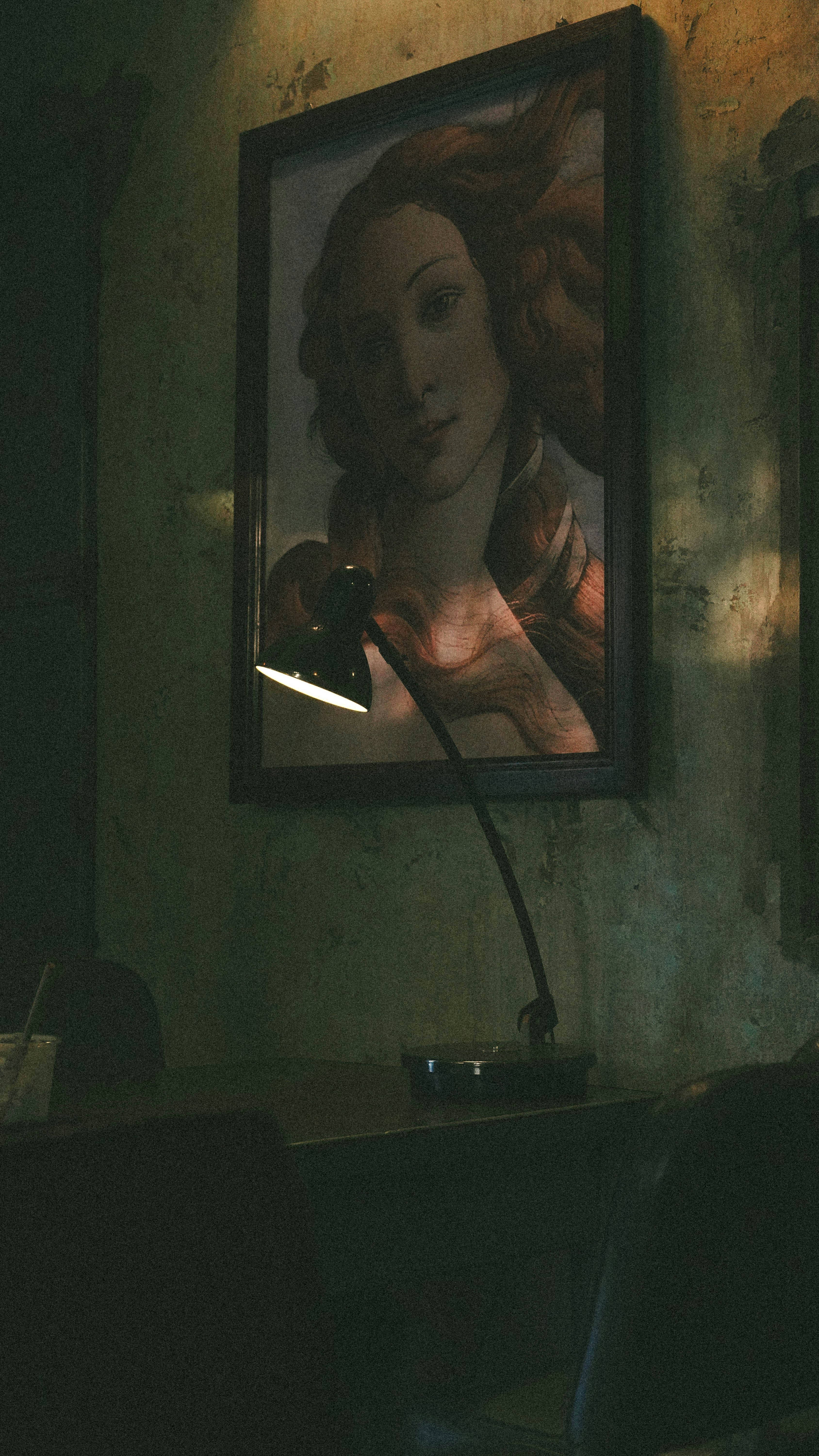 Dim Portrait in a Rustic Room: A Lamp Illuminates a Framed Figure