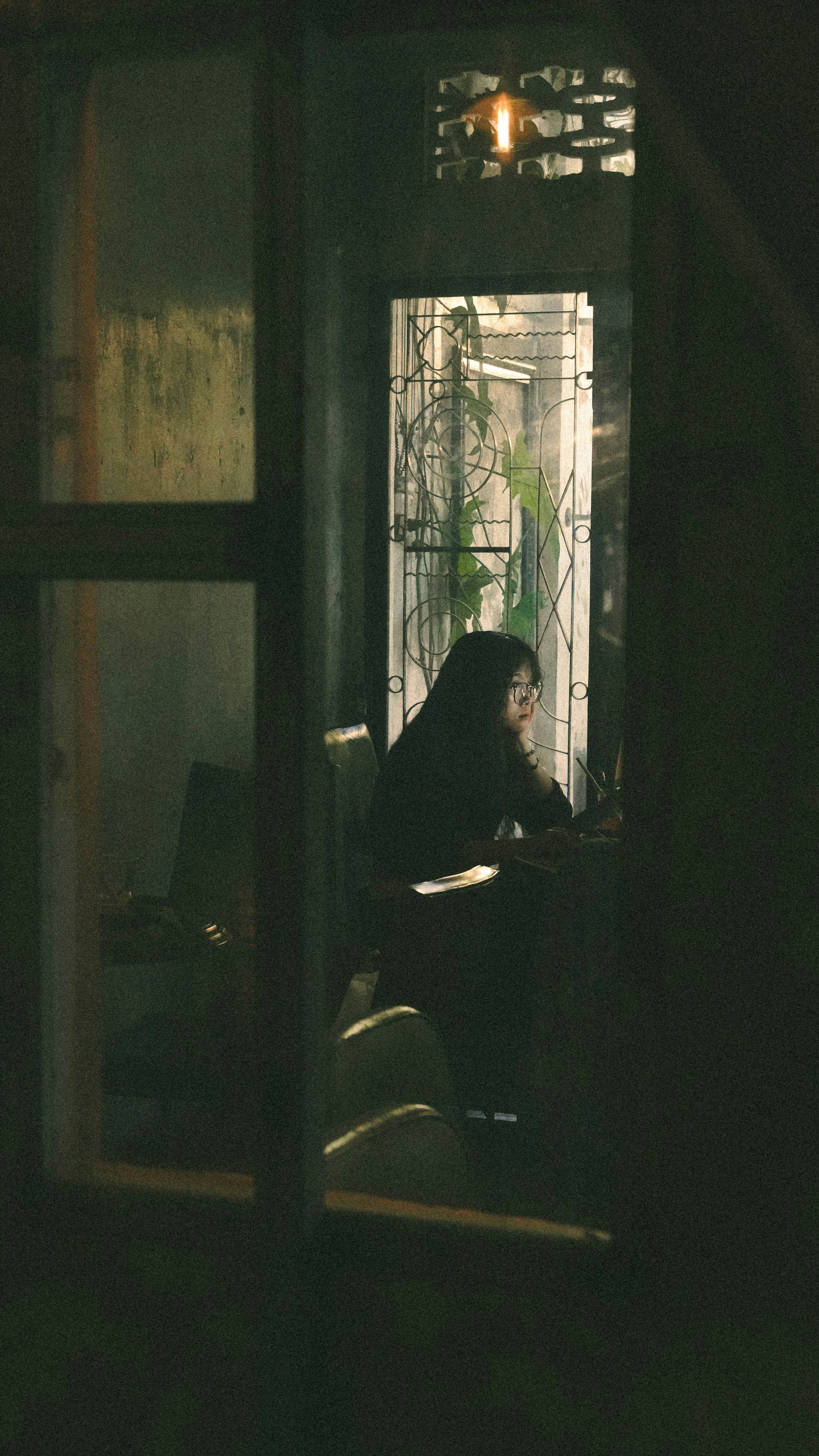 Quiet Vigil at the Window: A lone figure in dimly lit room