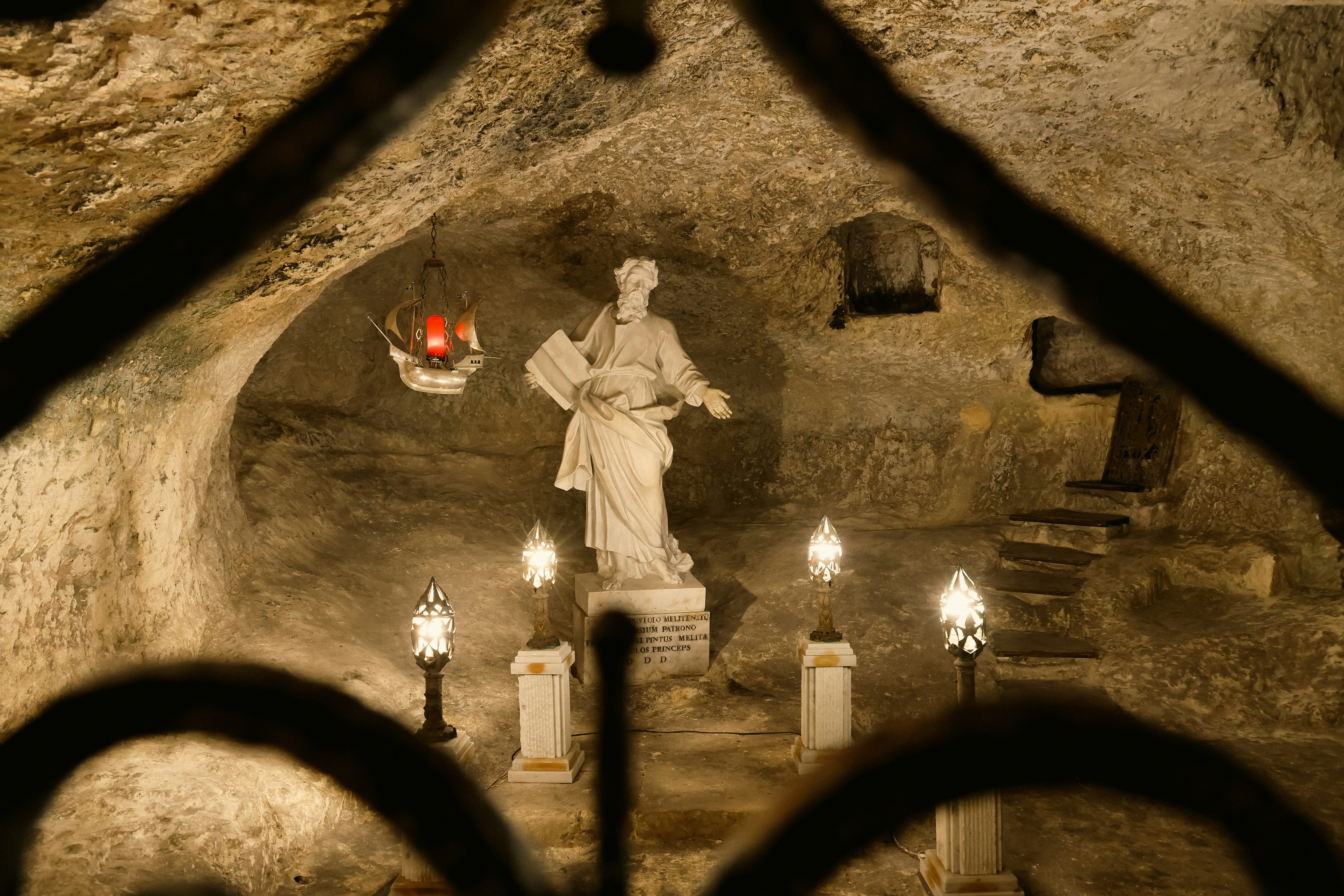 A white statue in a dimly lit cave with candles.