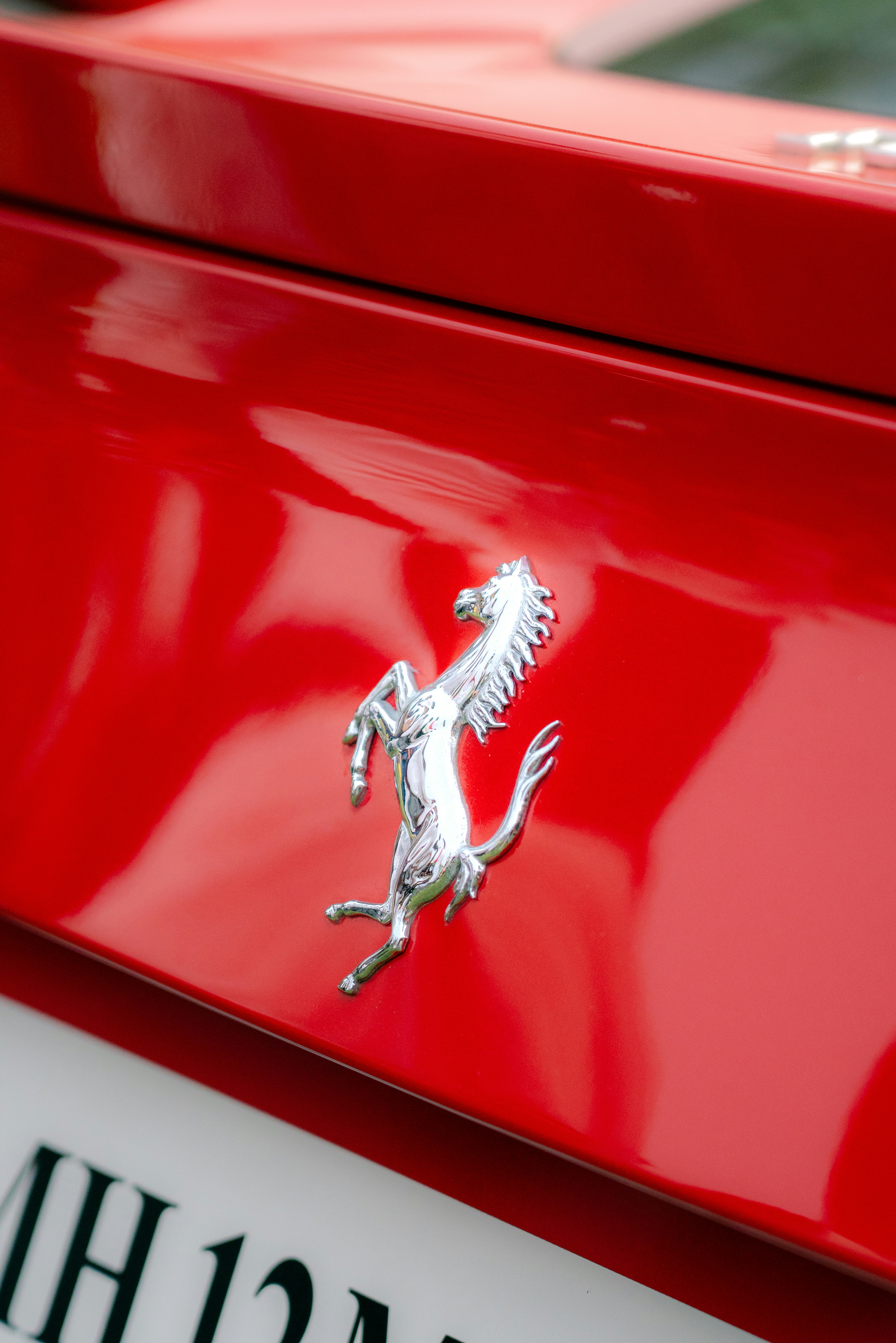 Silver Prancing Emblem on a Crimson Car Surface