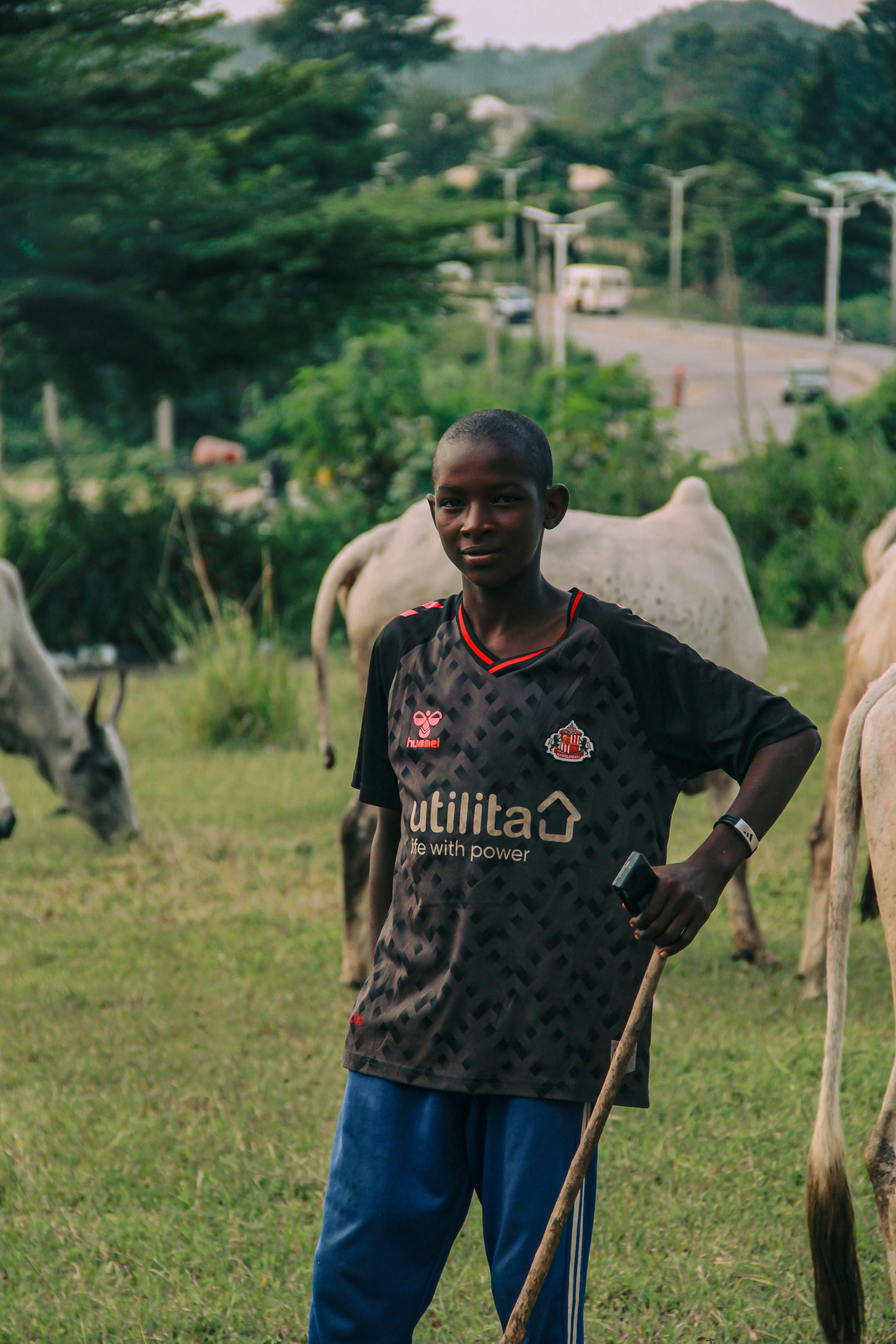 Youth in a Field, Herd of Camels in the Background