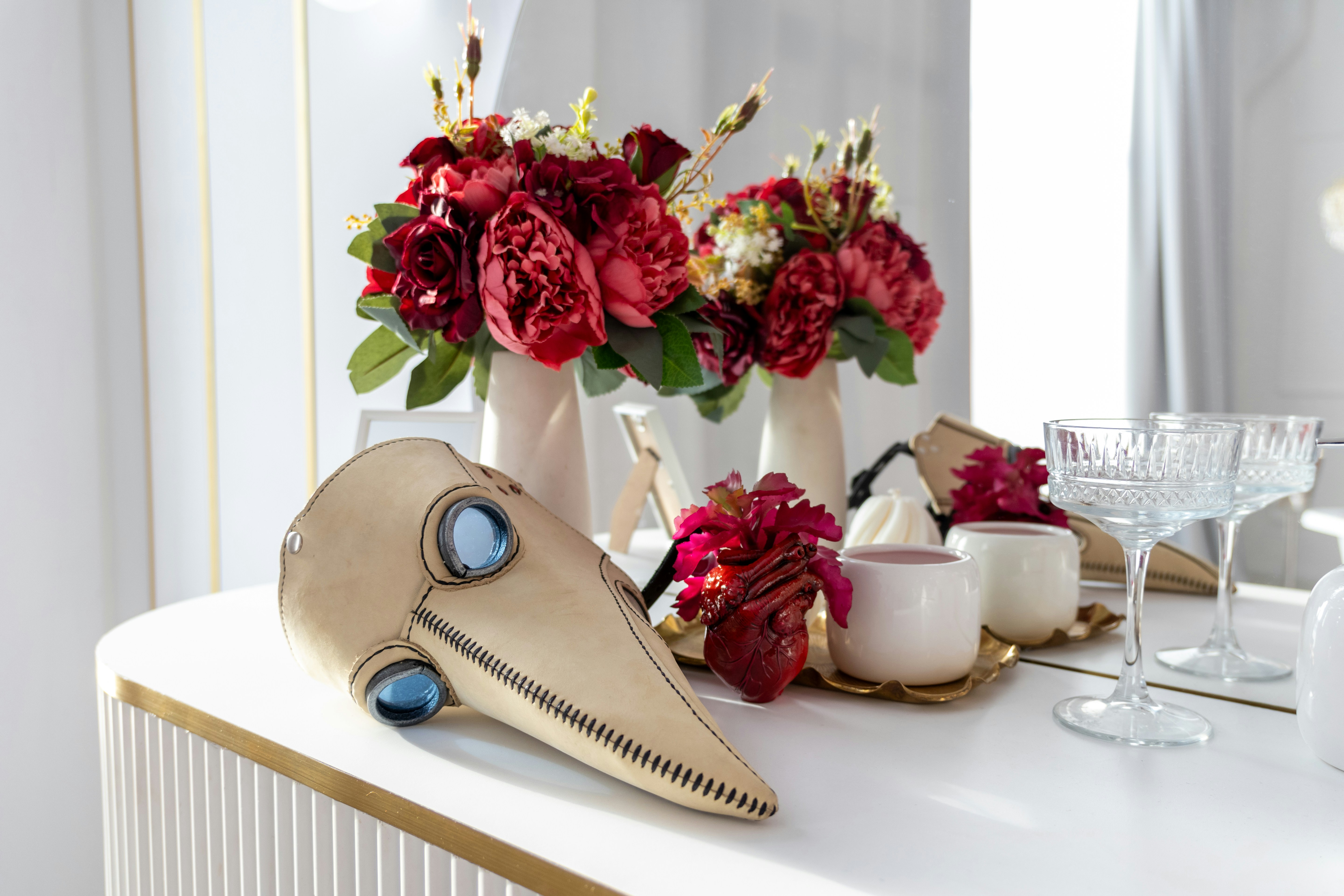 Masked Still Life: A Leather Beak and Crimson Arrangements on a Gleaming Table