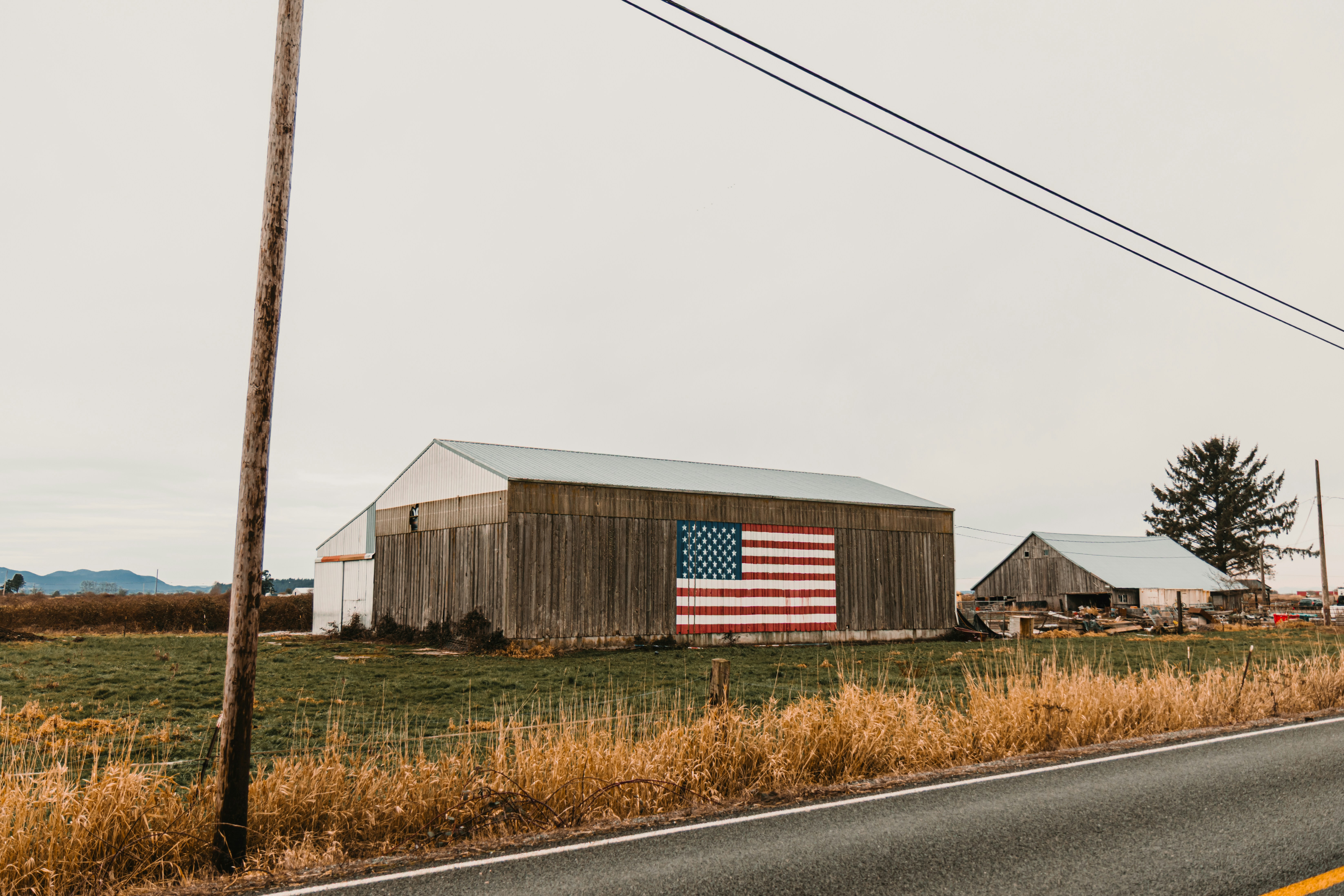 American Flag on Weathered Barn Under Wide Rural Sky