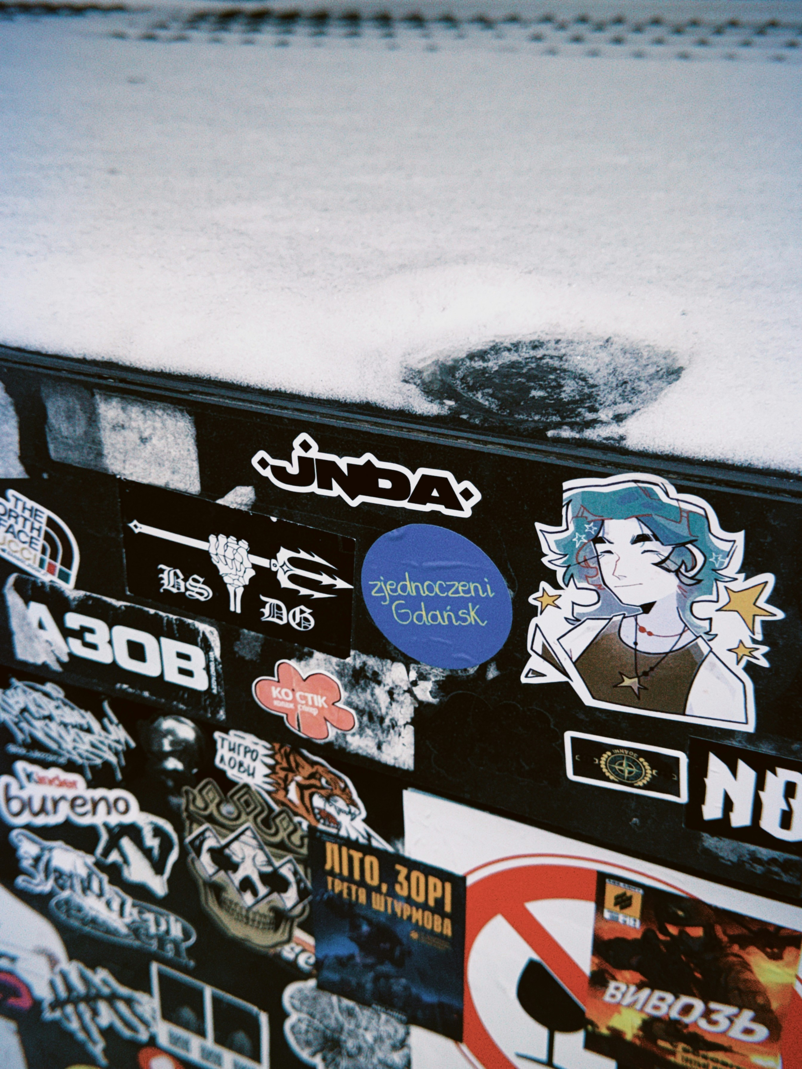 Sticker Mosaic on Snow-Capped Metal Surface