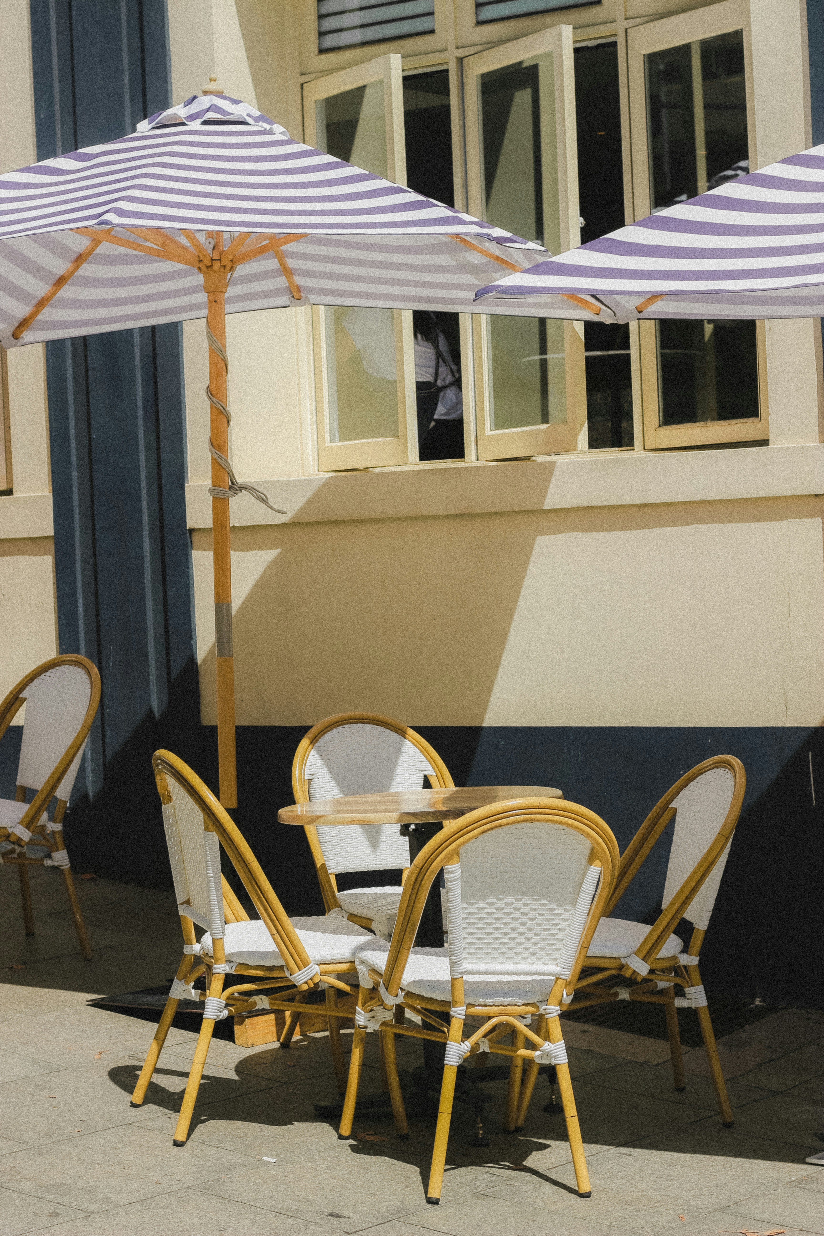 Straw-Stripe Oasis: A Quiet Patio of Woven Chairs and Sunlit Umbrellas