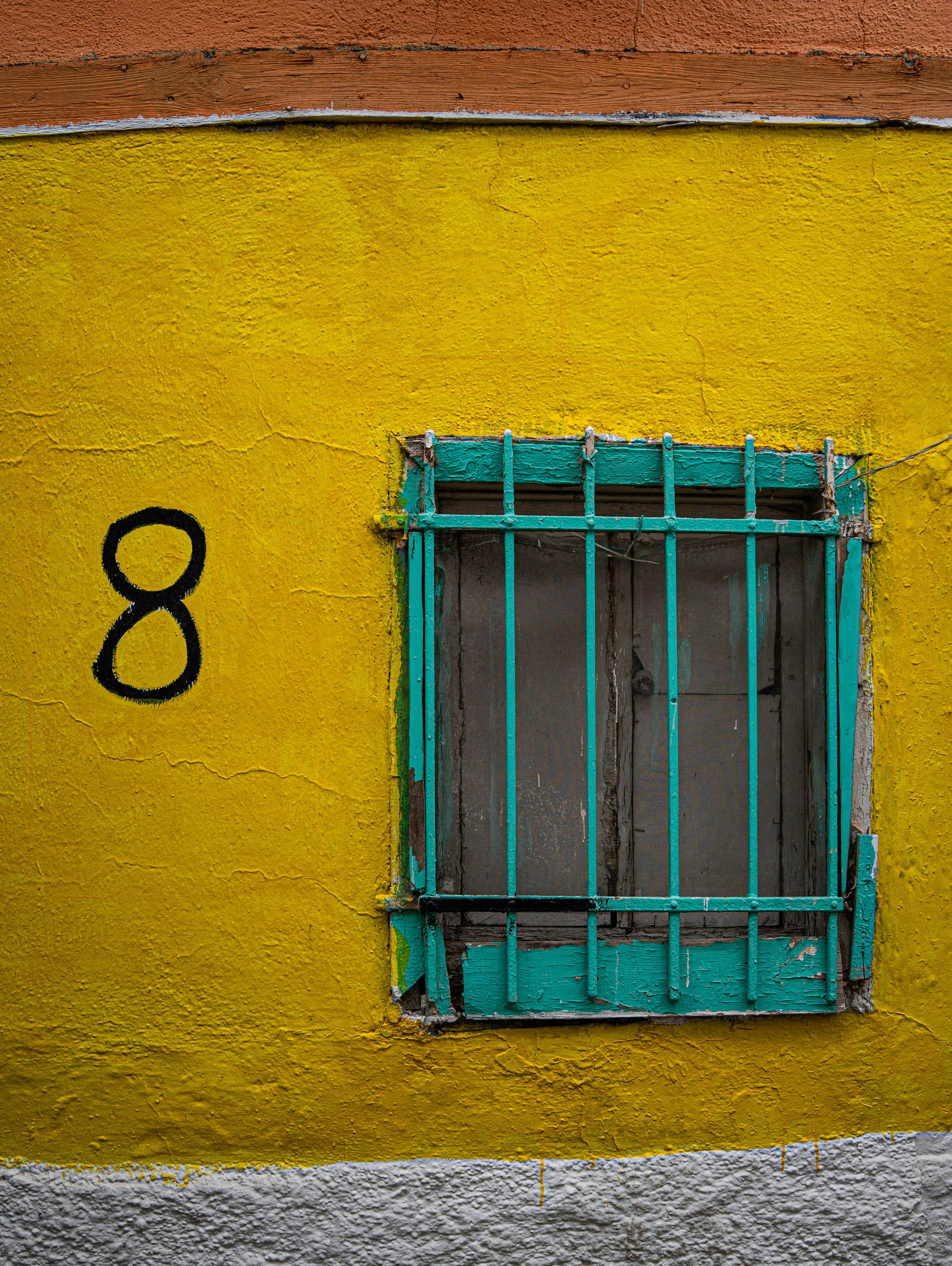 Una pared amarilla con una ventana turquesa y el número ocho. foto ...