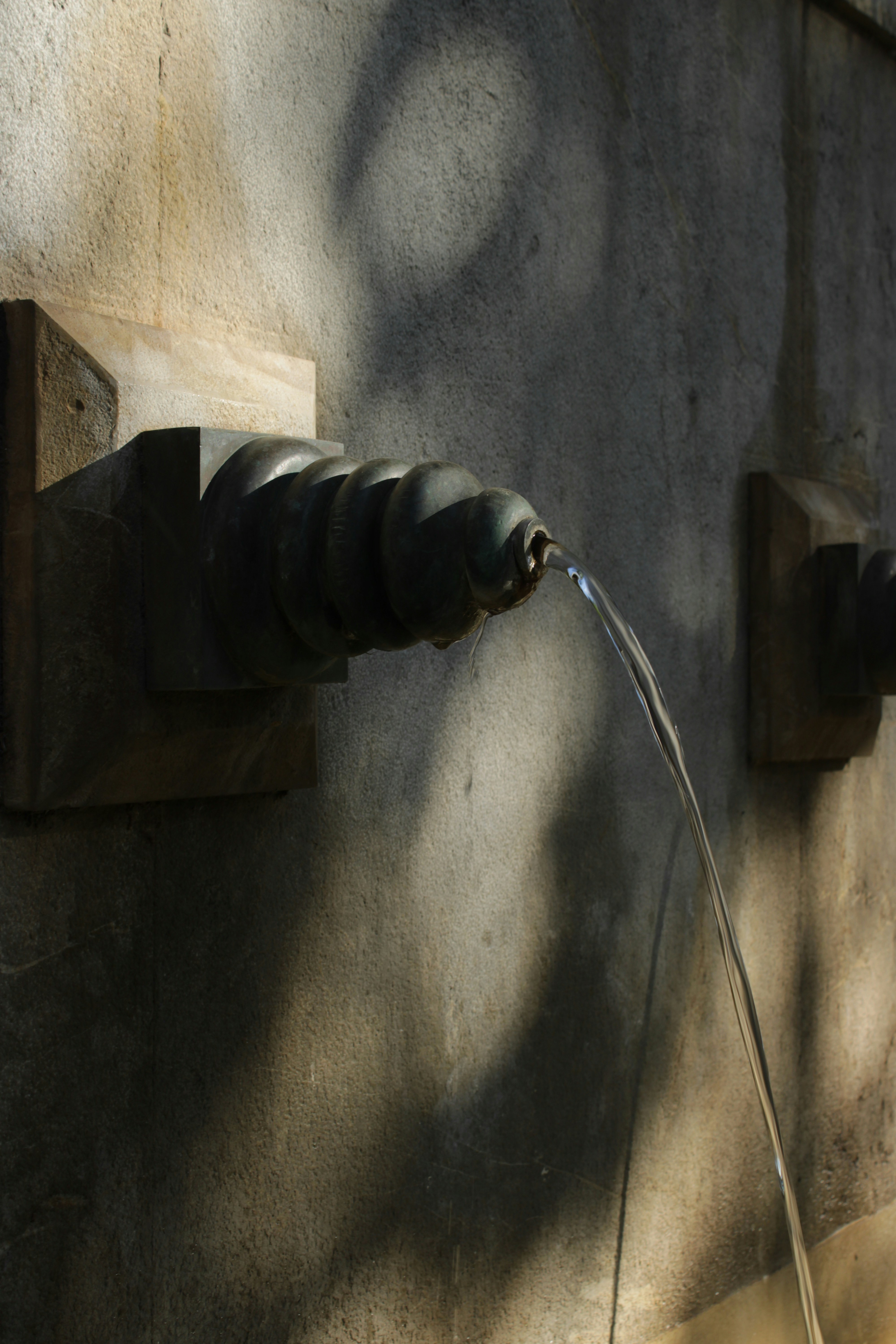Liquid Gravity: A Spout of Quiet Shadow on a Stone Wall