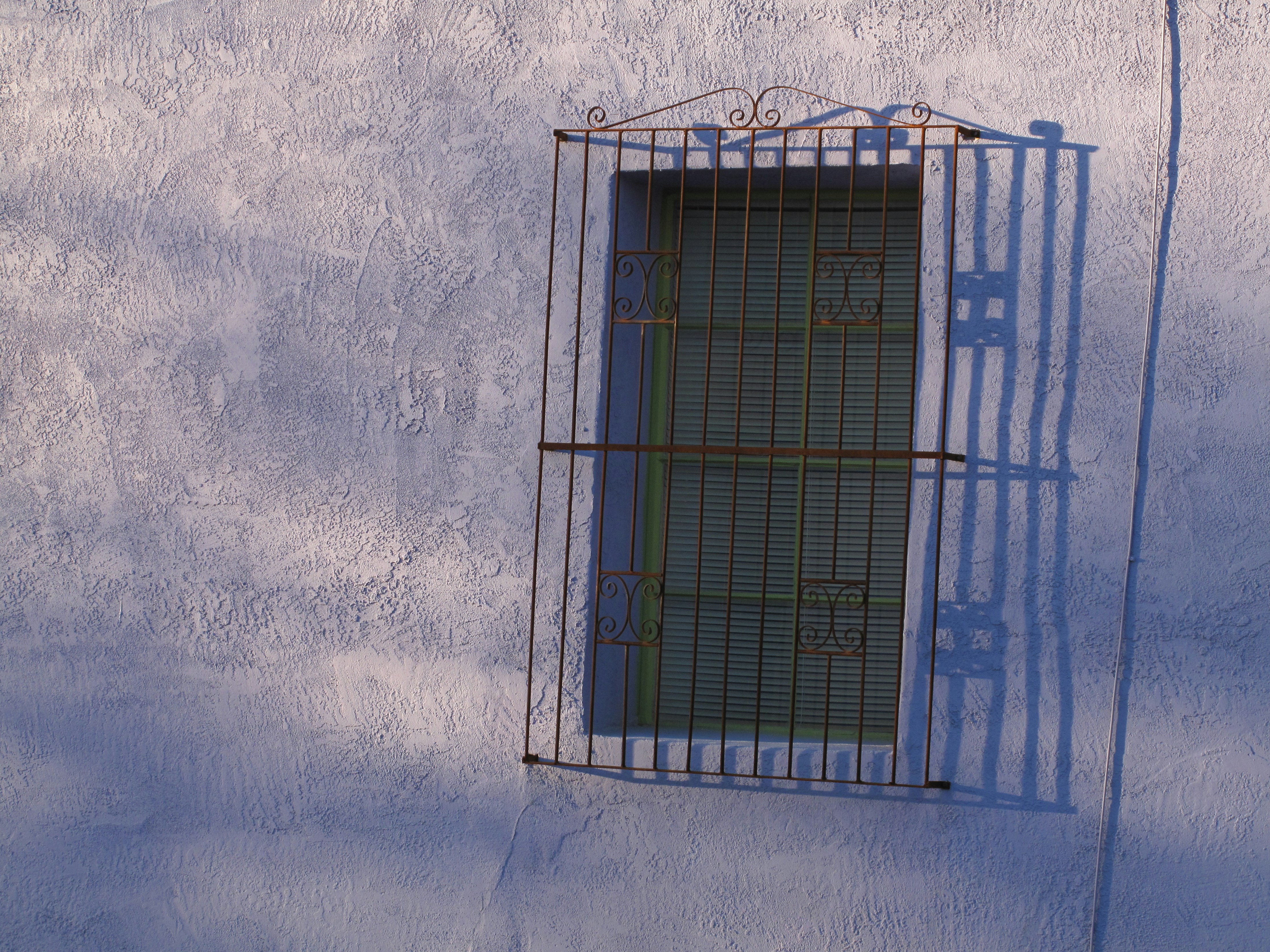 Window with metal bars casting striped shadows