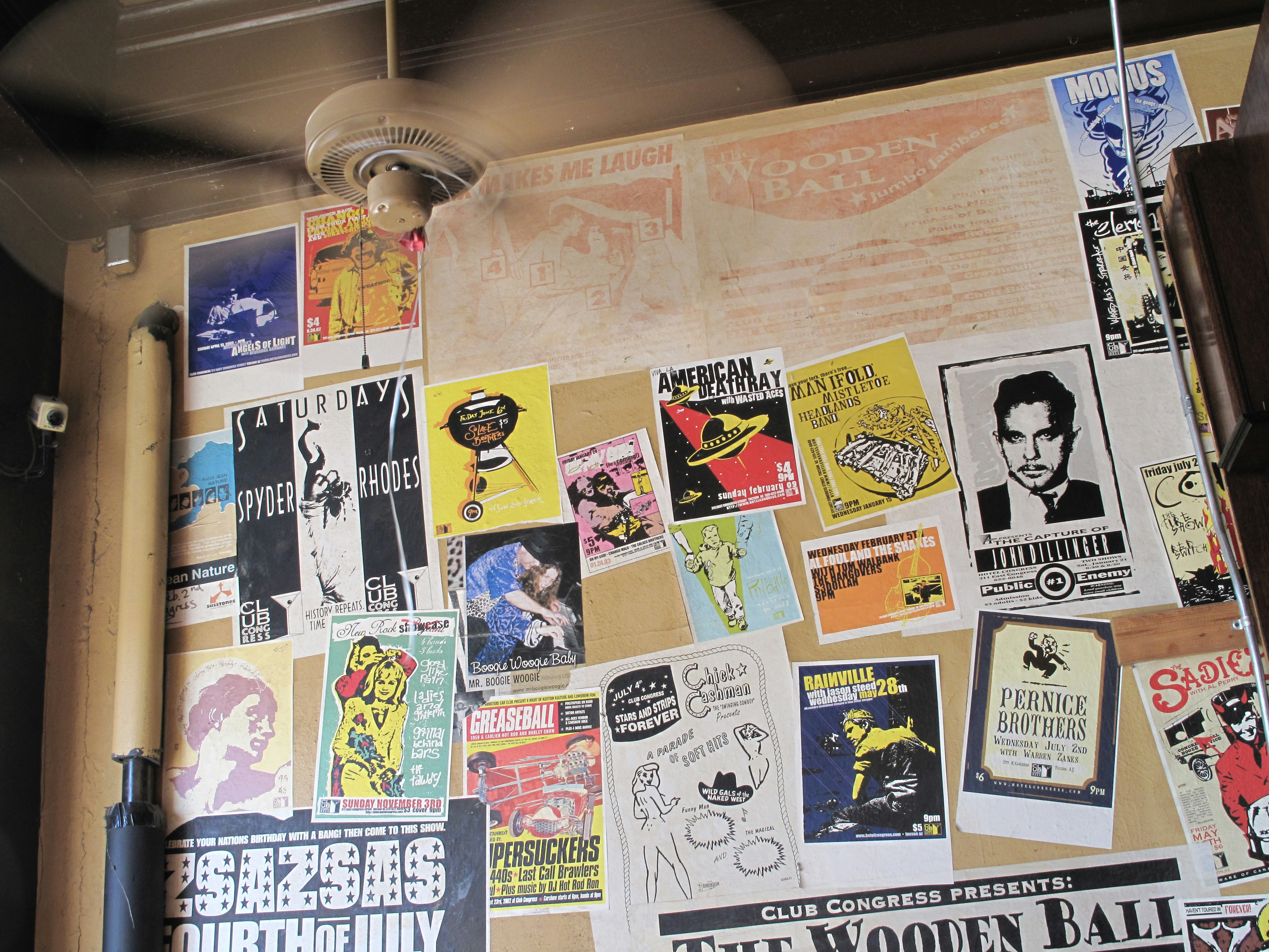 Wall covered in vintage posters and a ceiling fan.