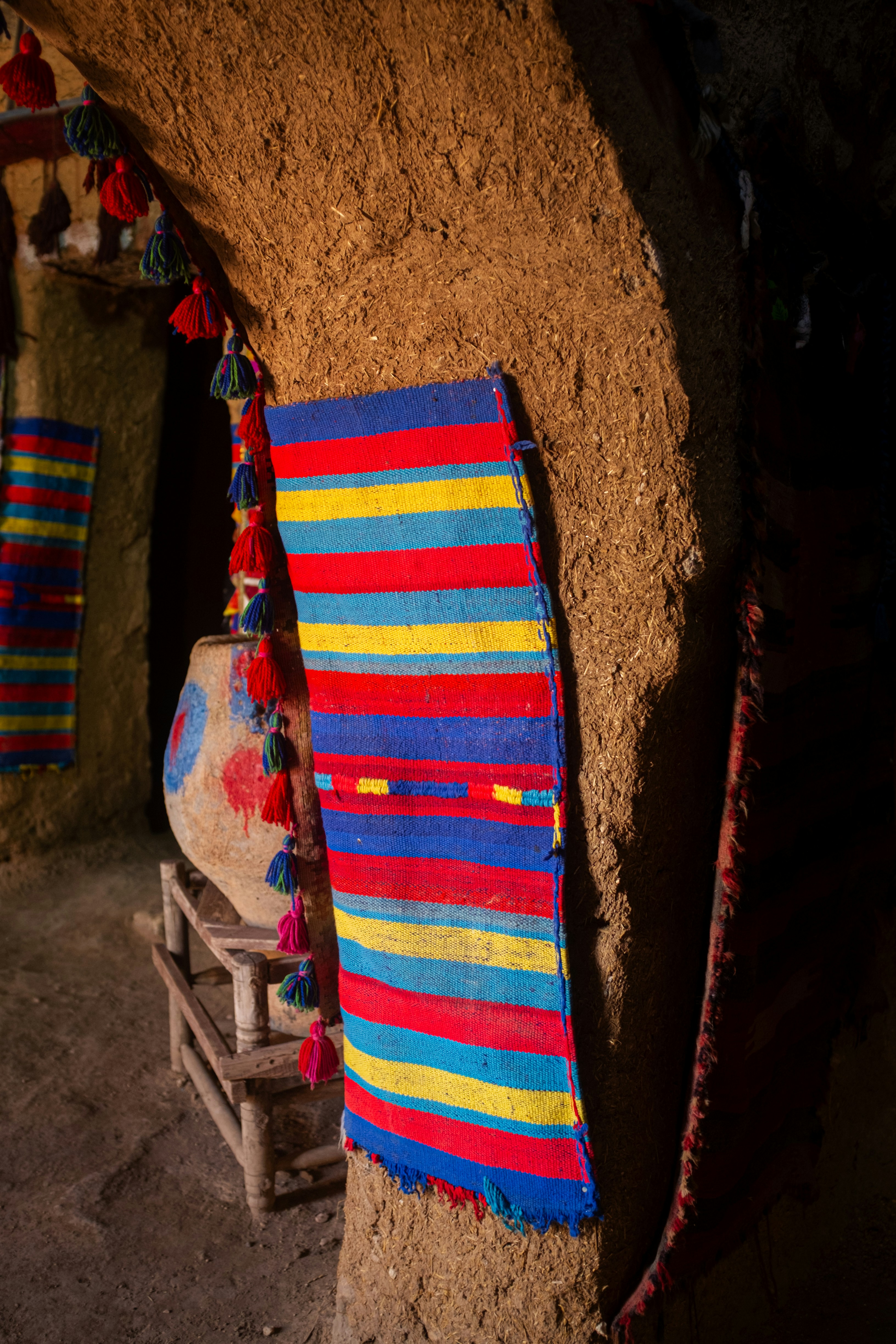 Colors of the Hearth: A Vibrant Rug Draped Over Earthen Wall