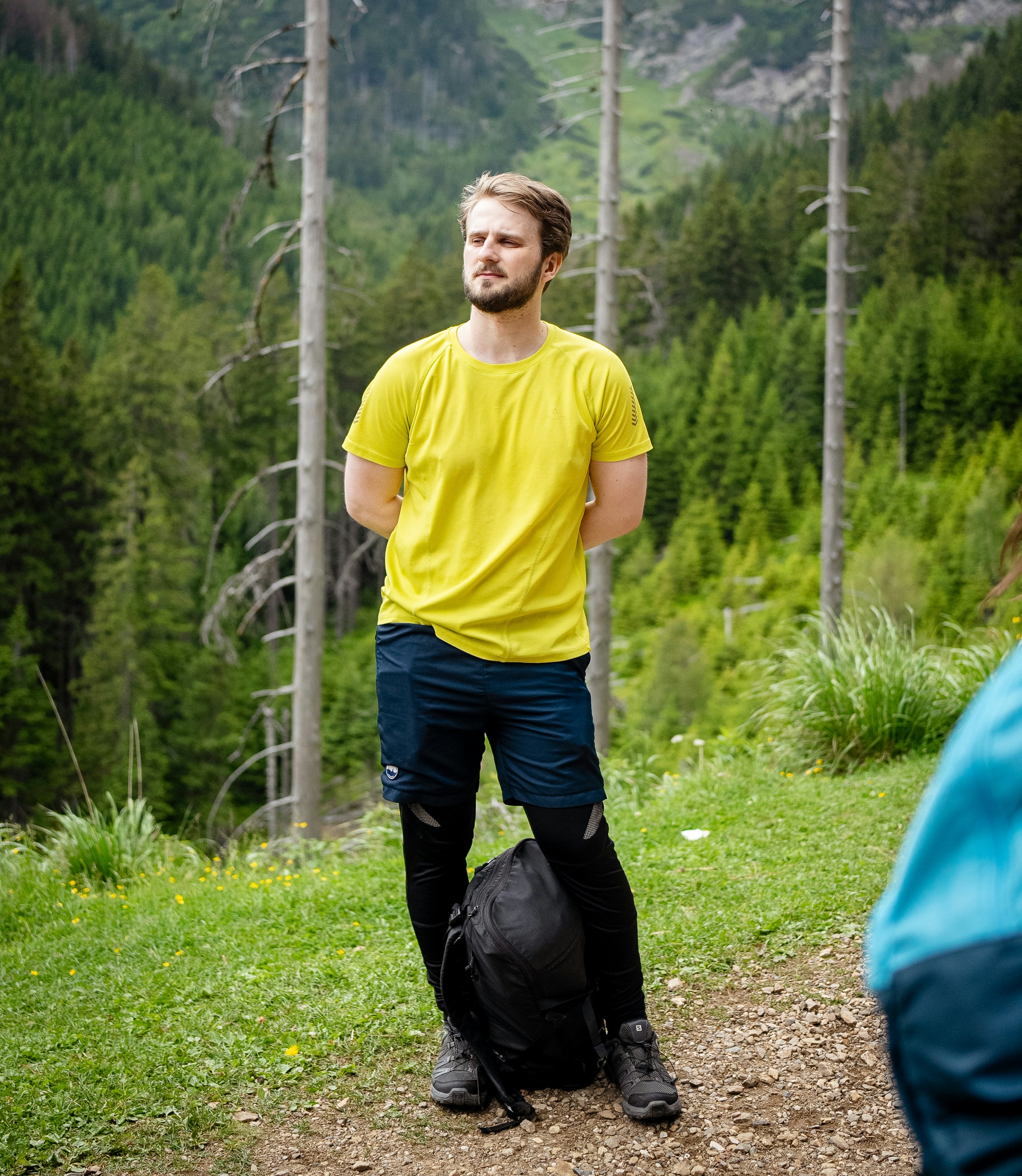 Yellow shirt in alpine clearing: a man pausing on a forested ridge