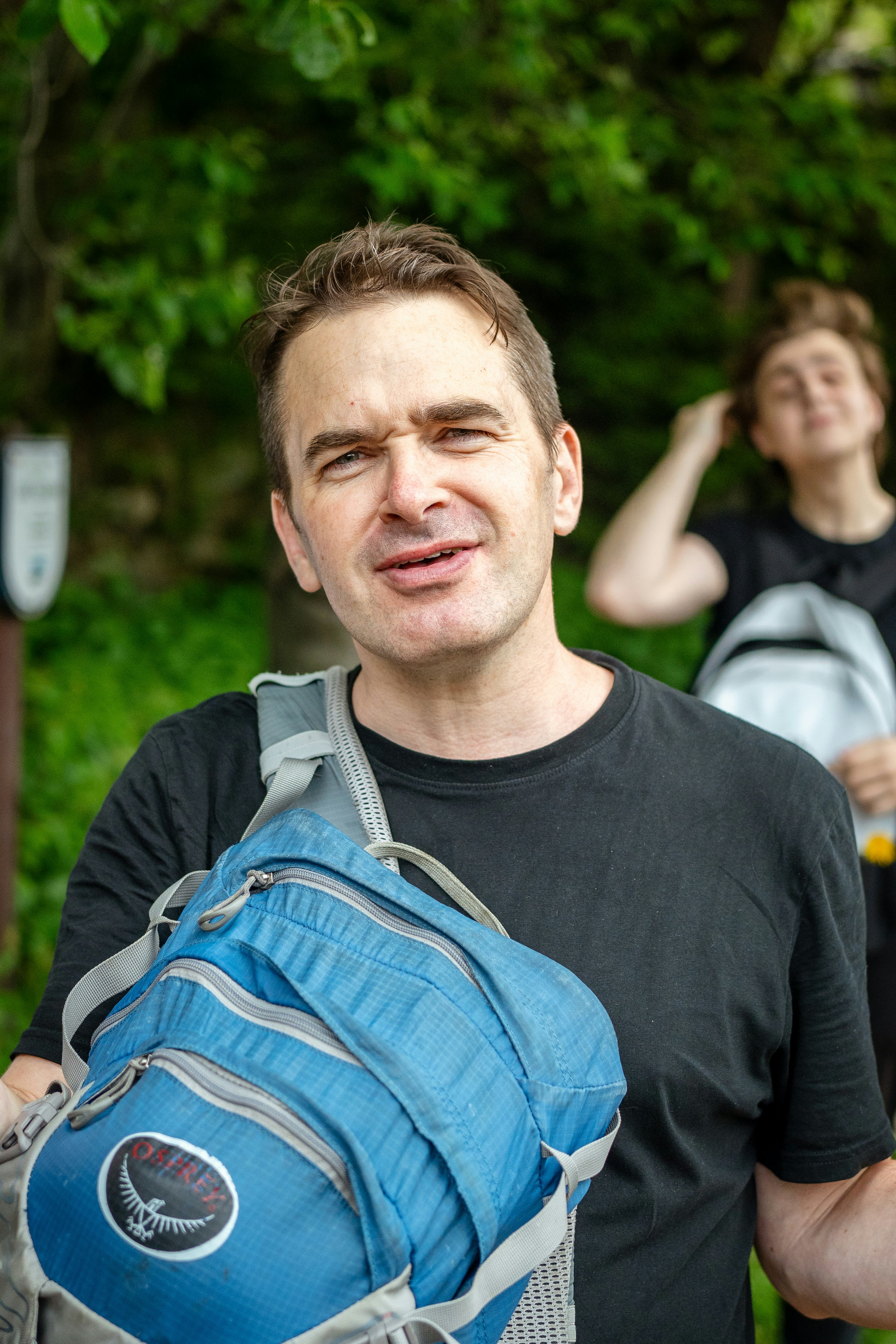 Friendly Guide in a Green Meadow: Portrait of a Hiker with Backpack
