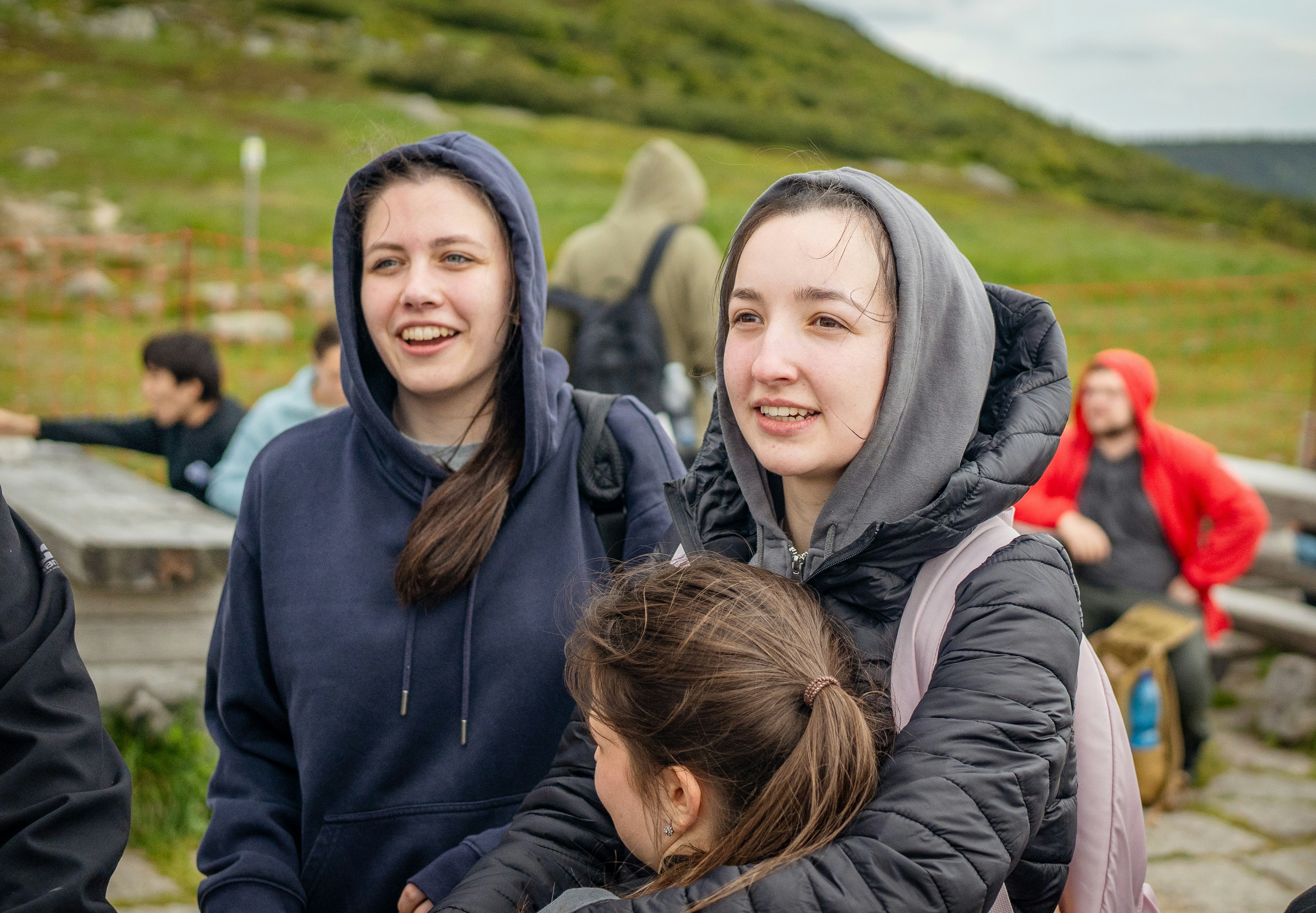 Group of teens at a coastal overlook, smiles under hoodies