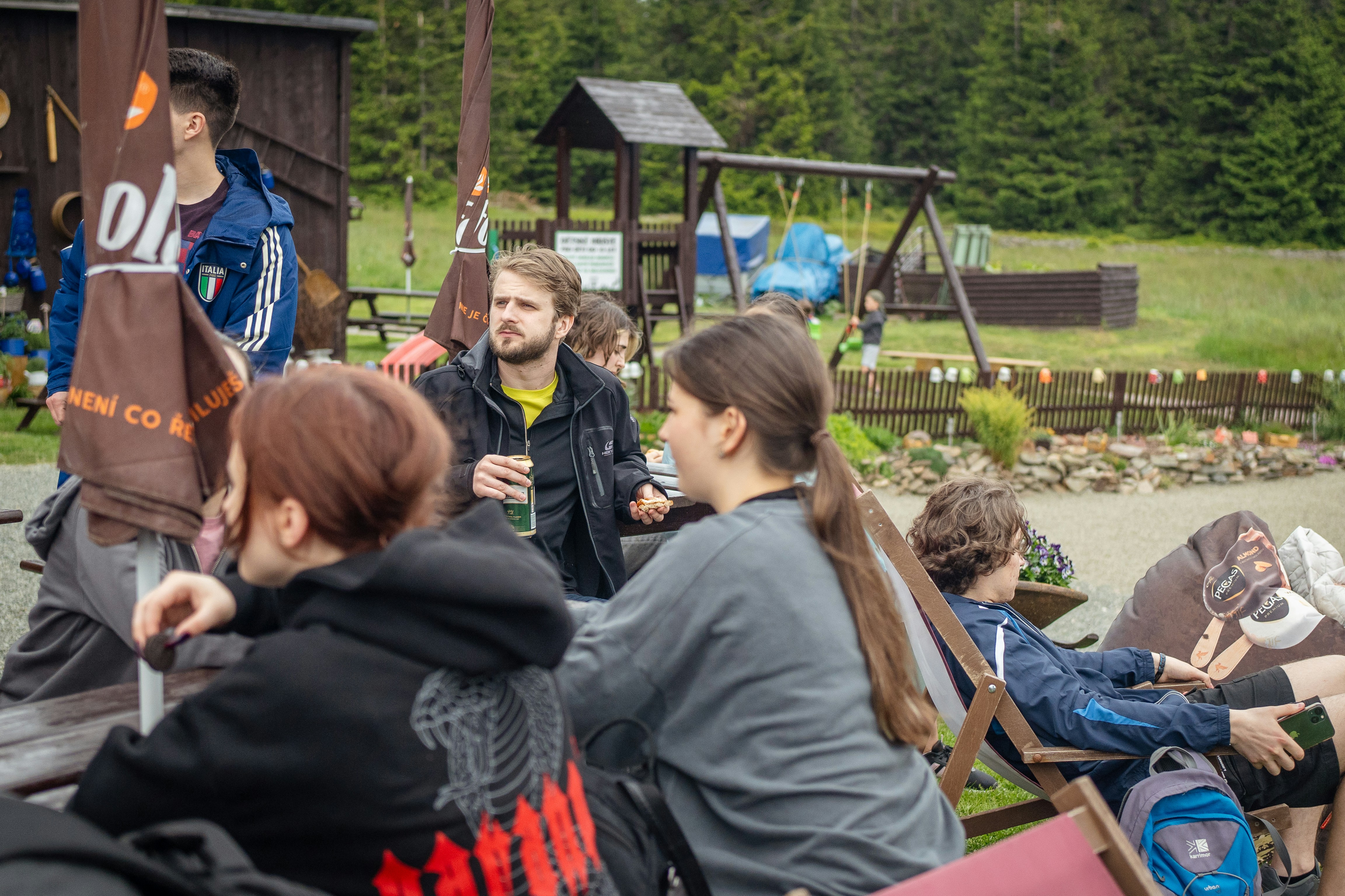 Group at a rustic outdoor venue: faces and conversations by a wooden play area