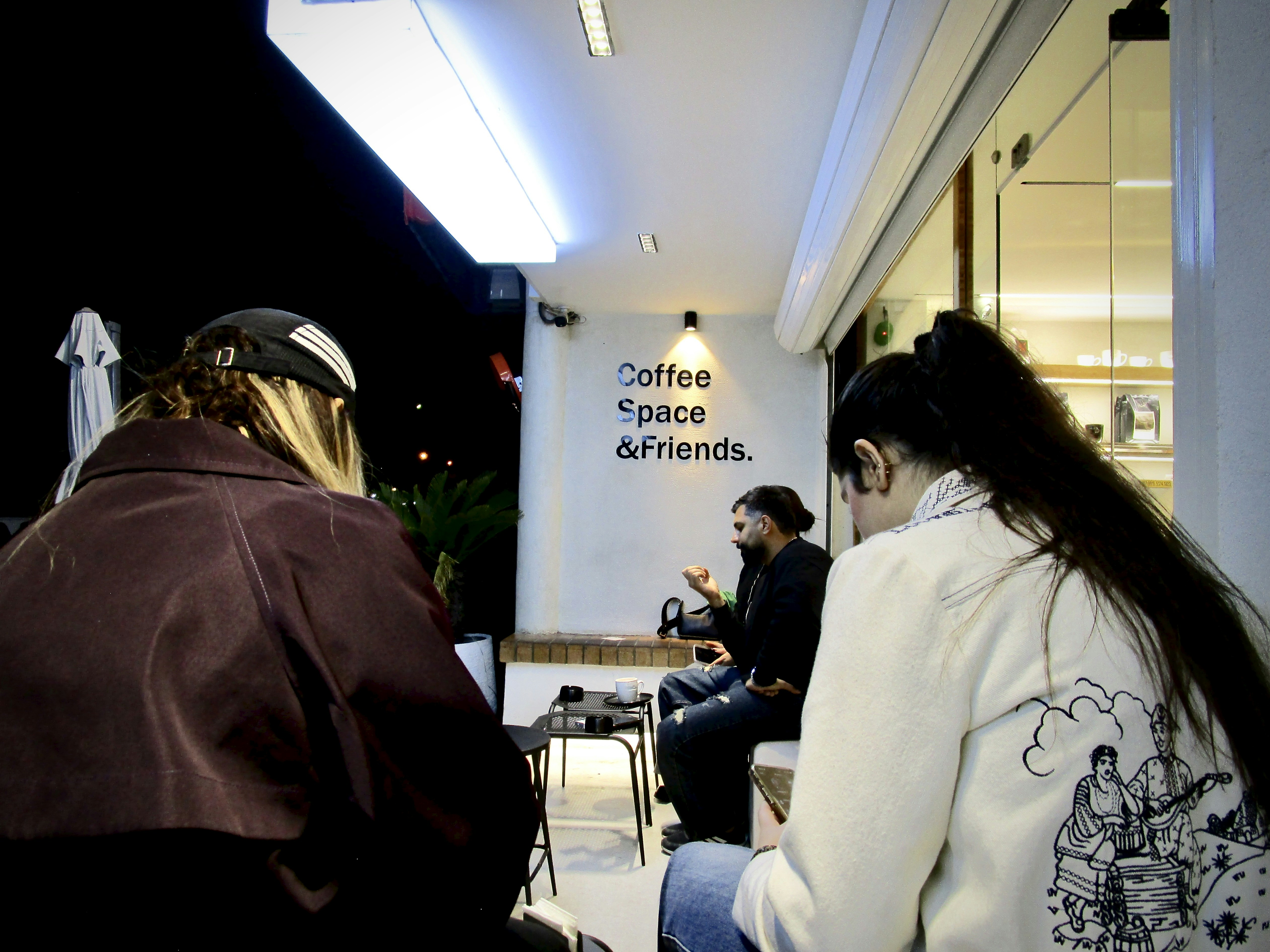 People gathered outside a coffee shop at night.