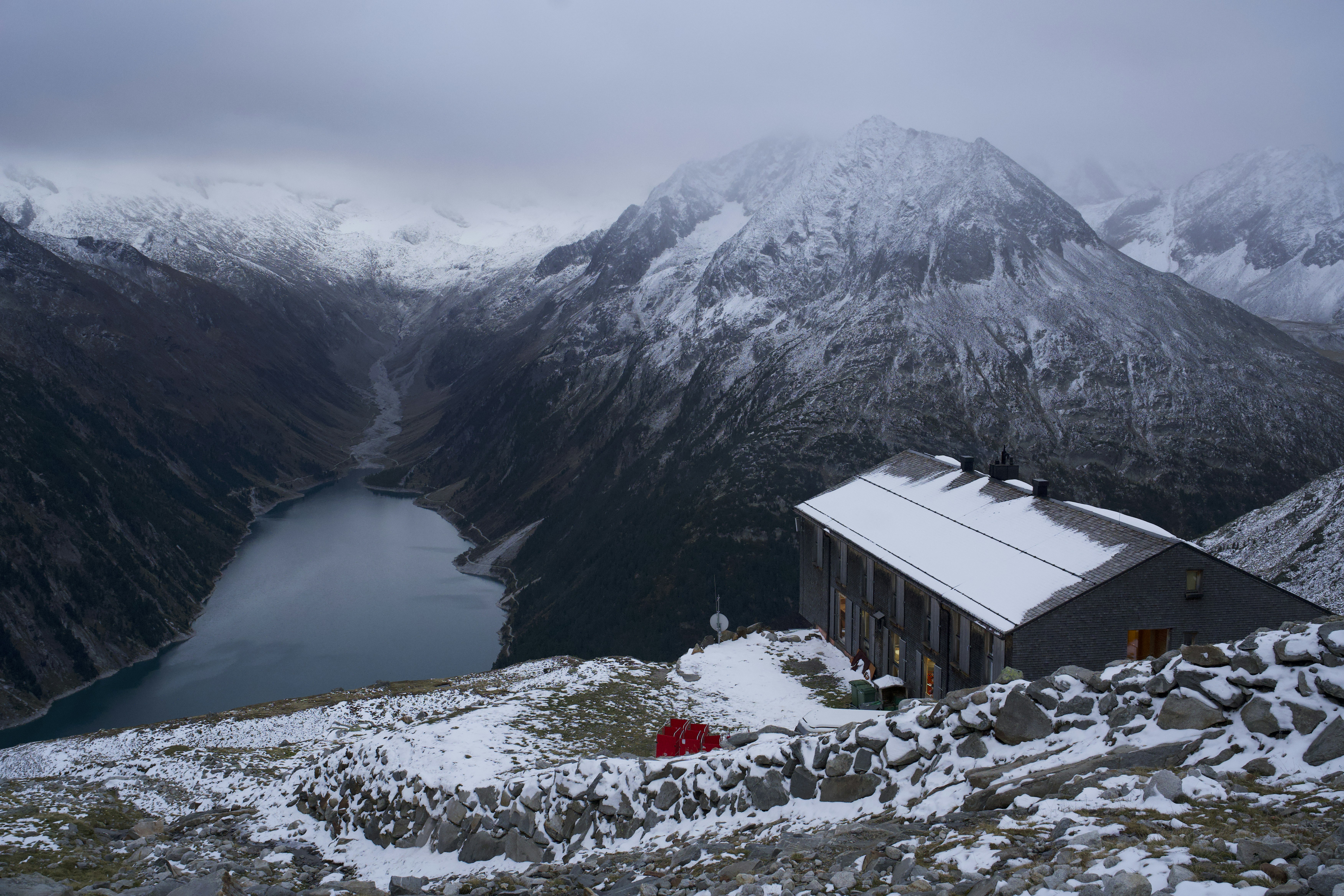 Snowbound refuge on a windswept cliff overlooking an alpine lake