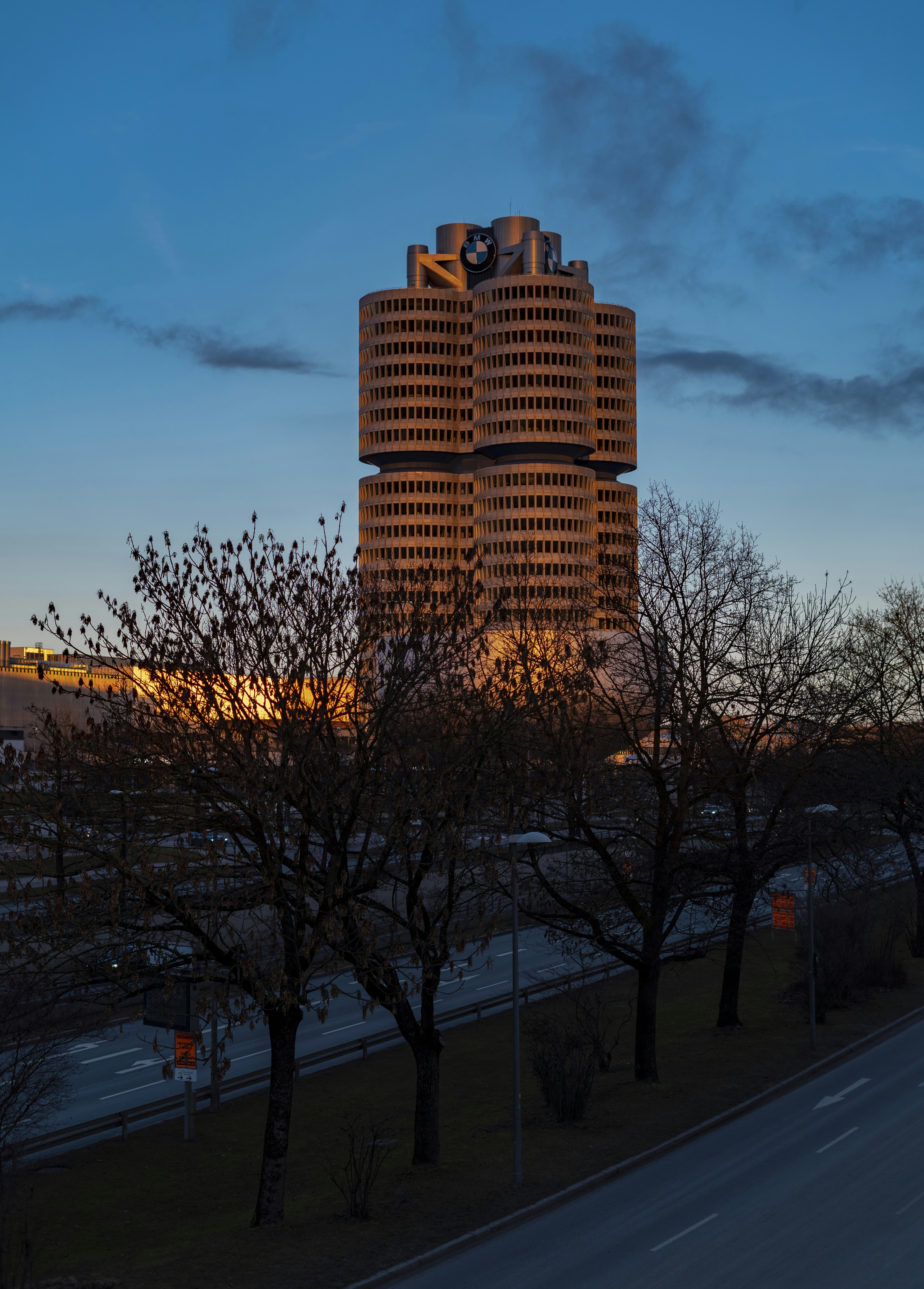 Twin Cylinders at Dusk: A Silhouette of the BMW Building Rising Over Quiet Trees