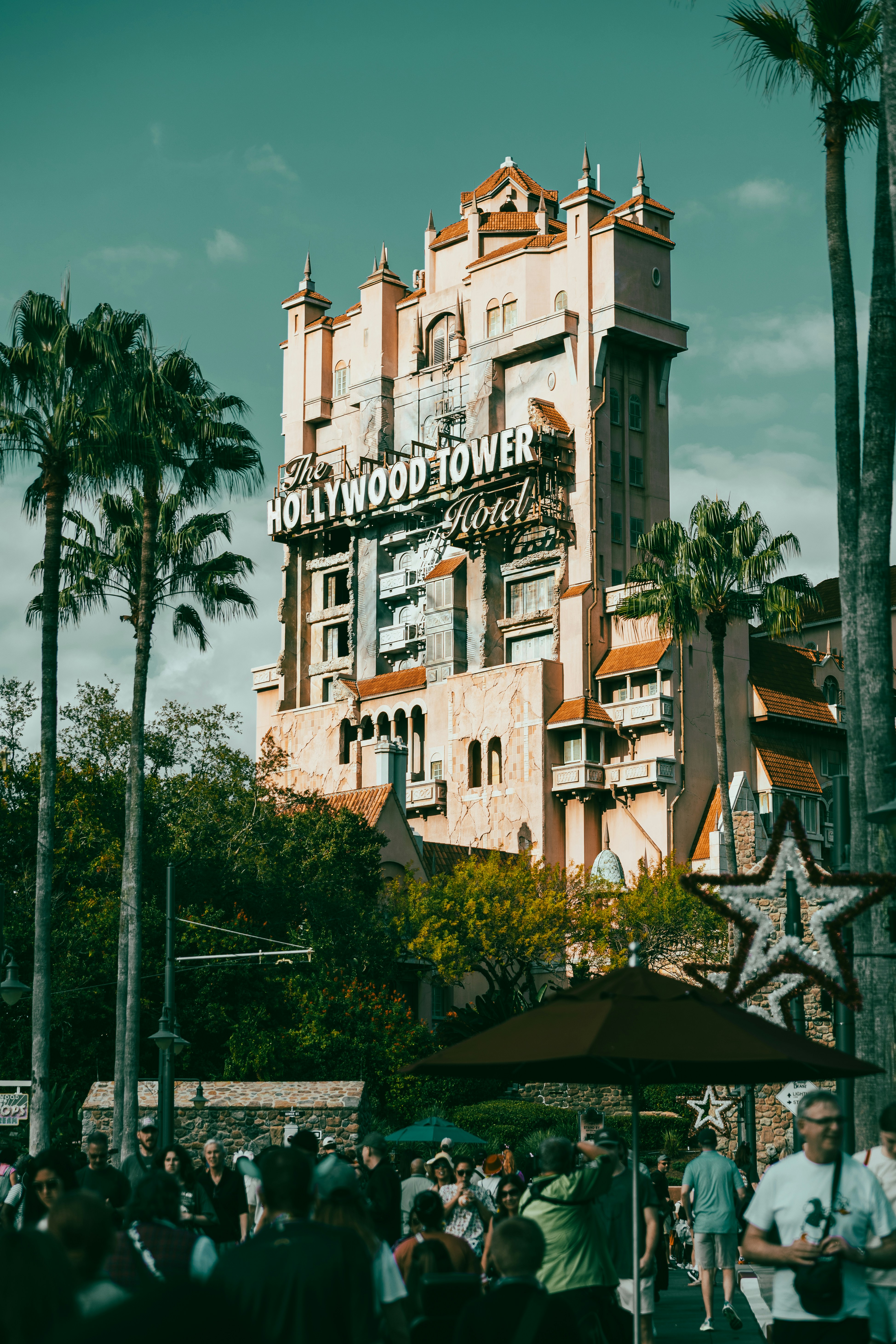 Hollywood Tower at Dusk: Palm Trees, Neon Sign, and a Crowd