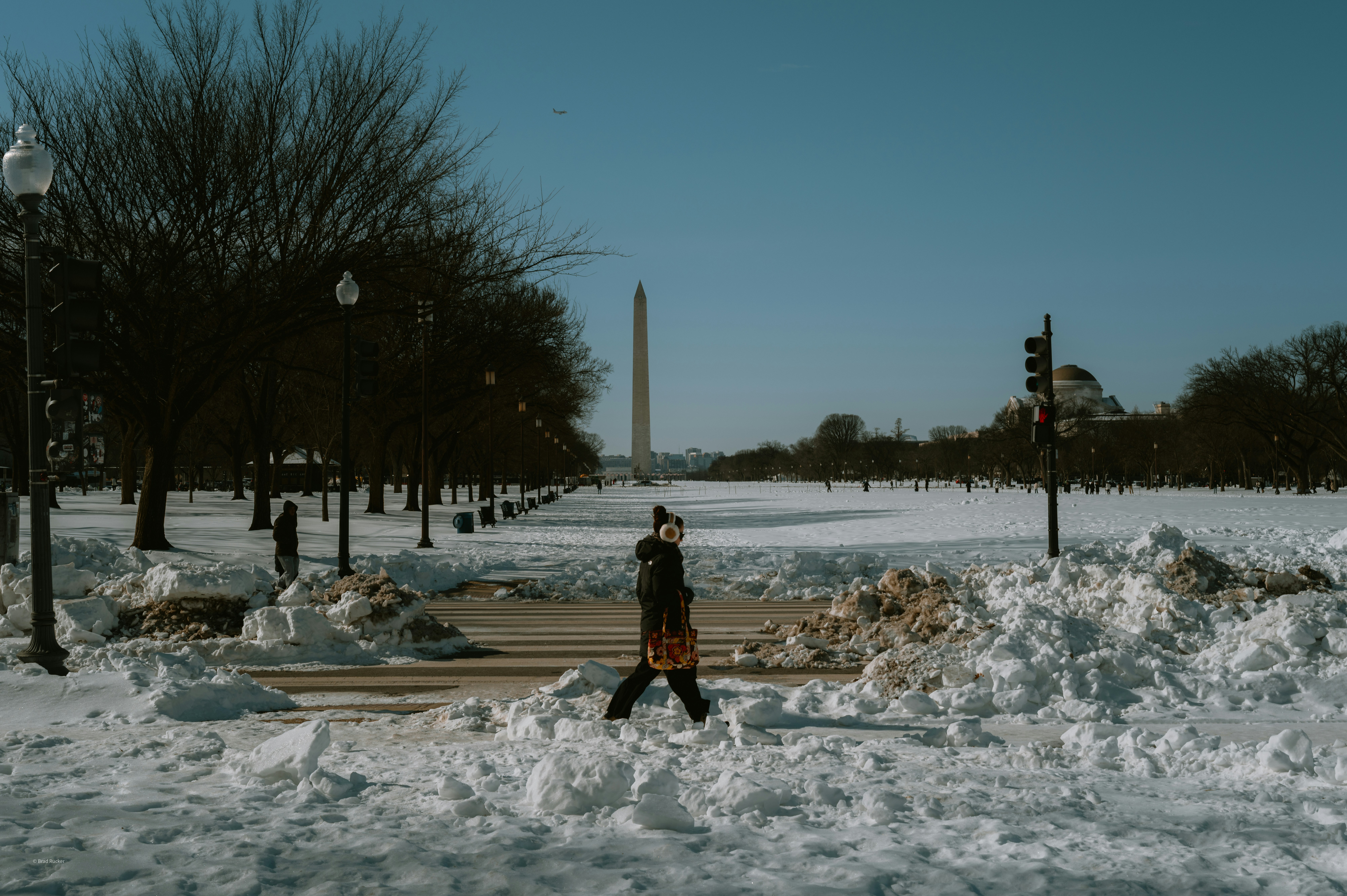 Winter Walk at Center Stage: A Couple Amid the Snowy Mall Leading to the Washington Monument