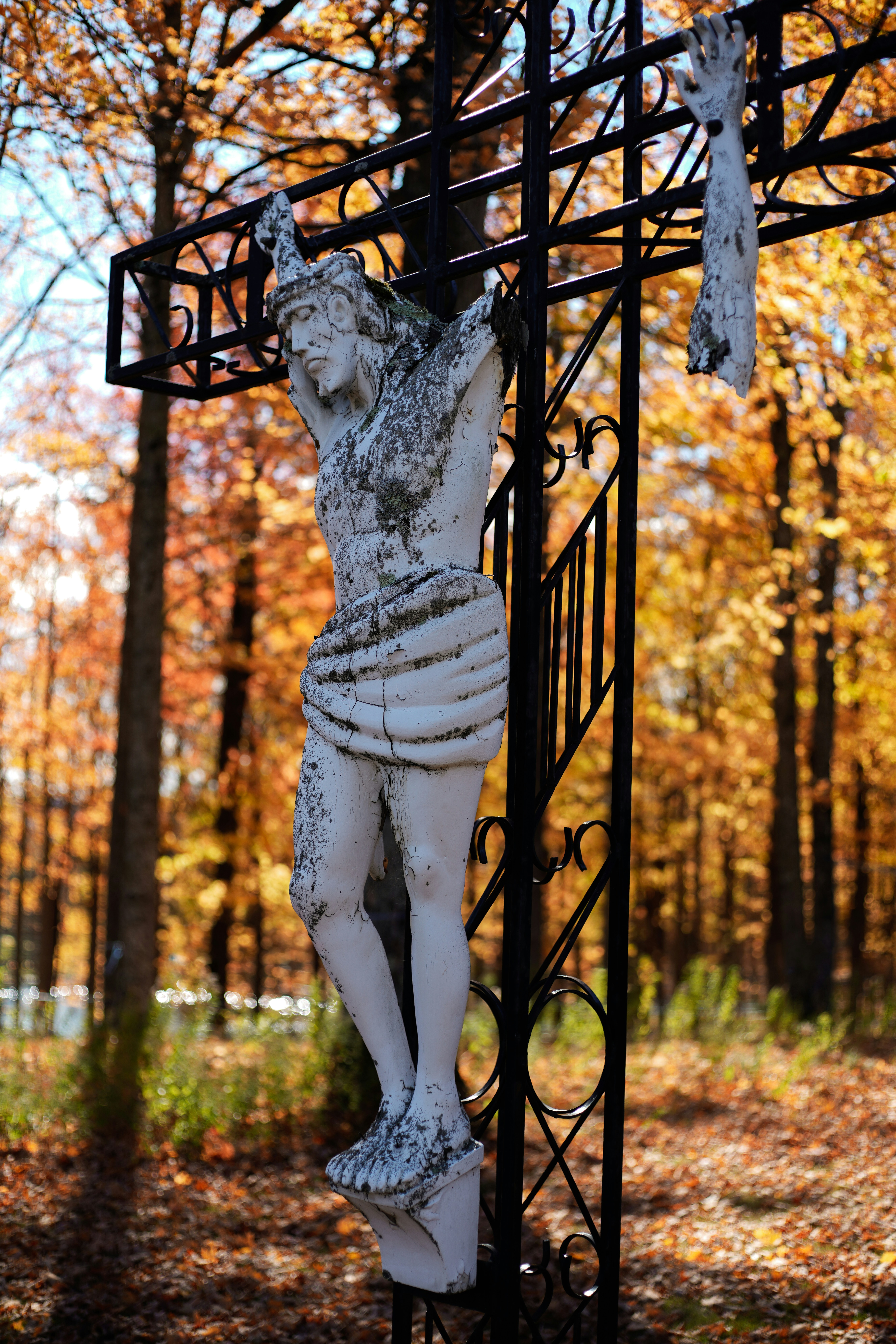 Crucifixion in Autumn Light: A Weathered Statue Clings to Iron Cross
