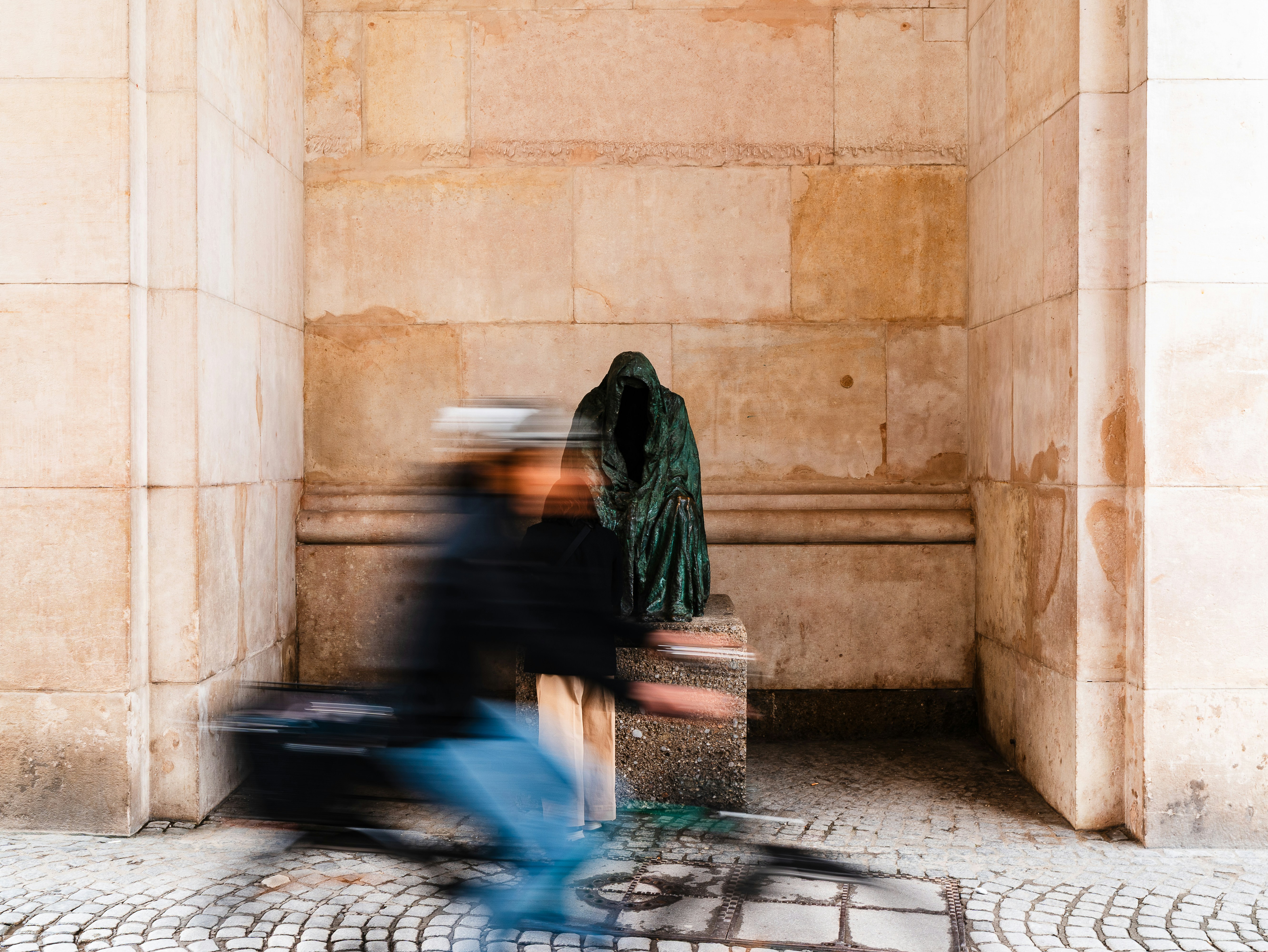 Blurred Pedestrian in Front of a Green Draped Statue