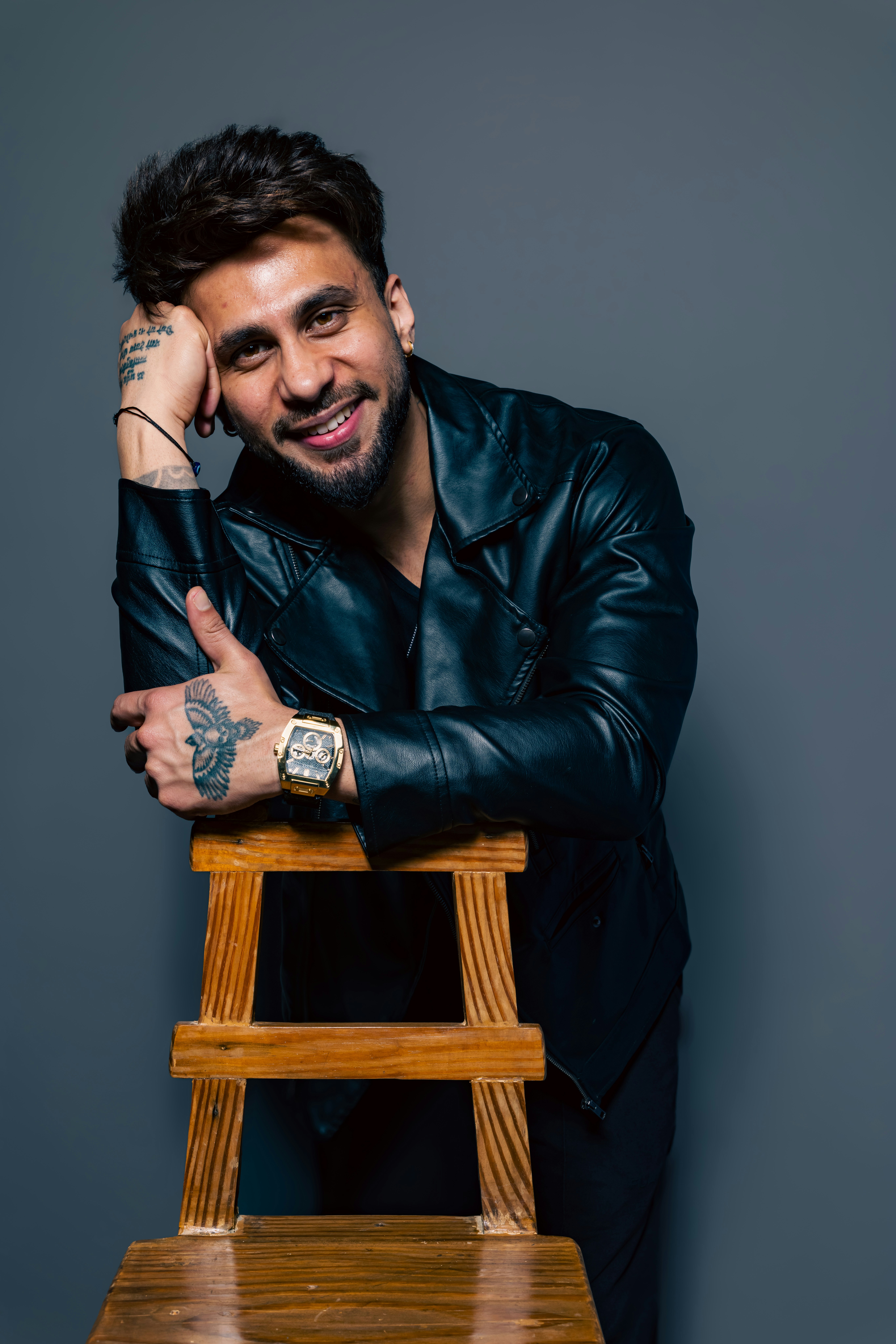 Leather-clad portrait: relaxed pose with a wooden stool