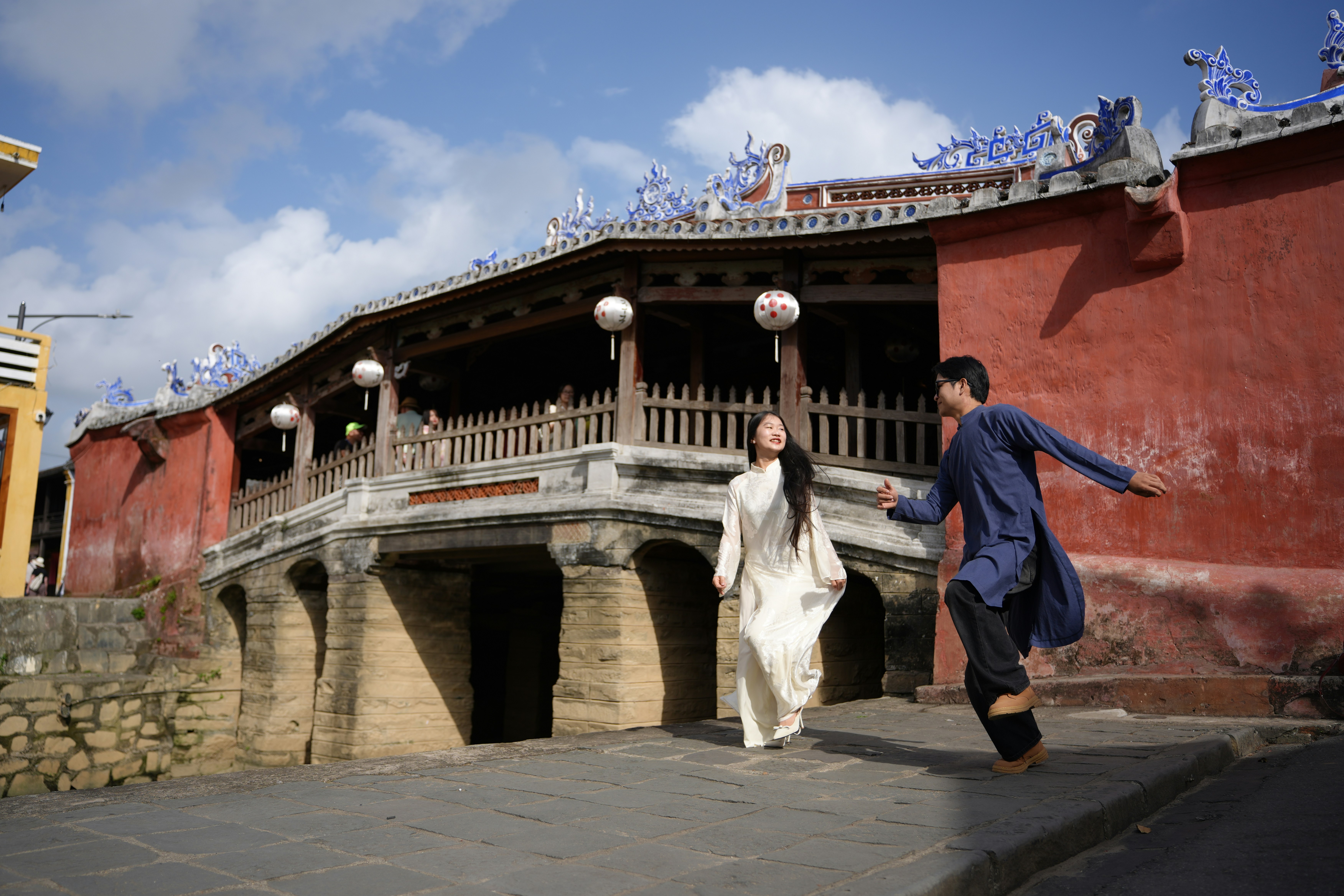 Dance of Light and Heritage: A Couple in Motion Before the Red Temple Wall