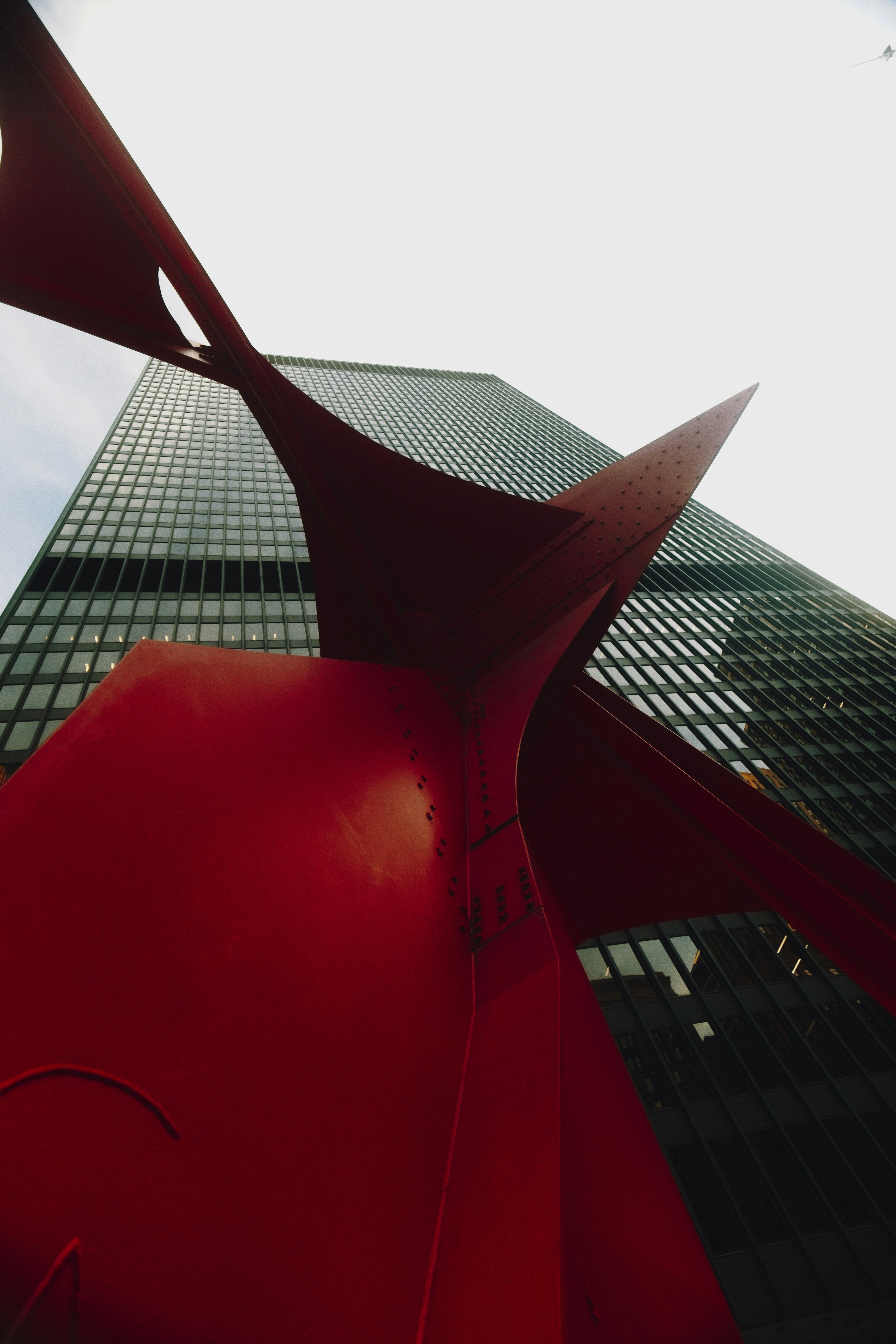 Red Sculptural Fragments Reach Toward Steel Sky