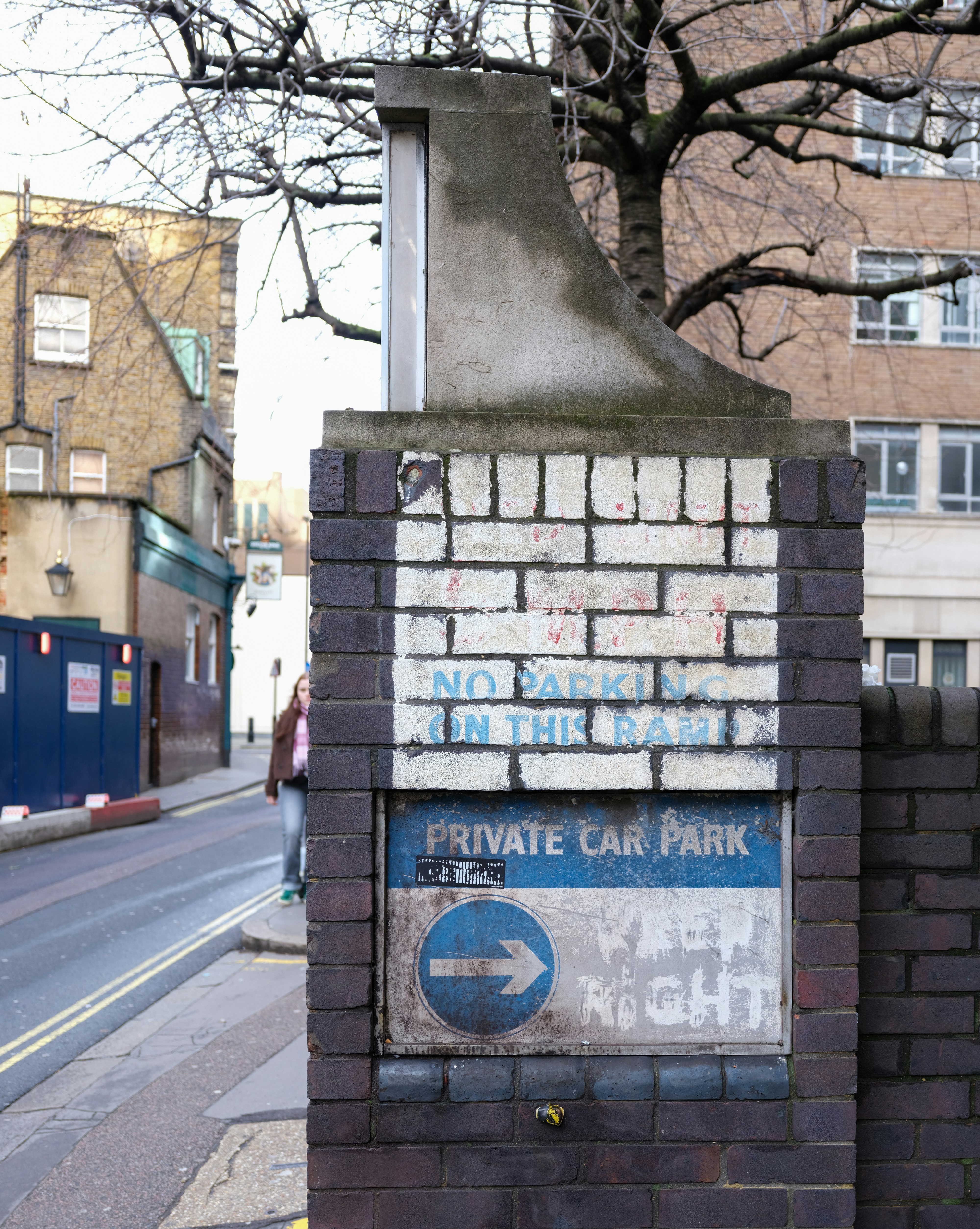 Brick Pillar with Weathered Signage at a Narrow City Street