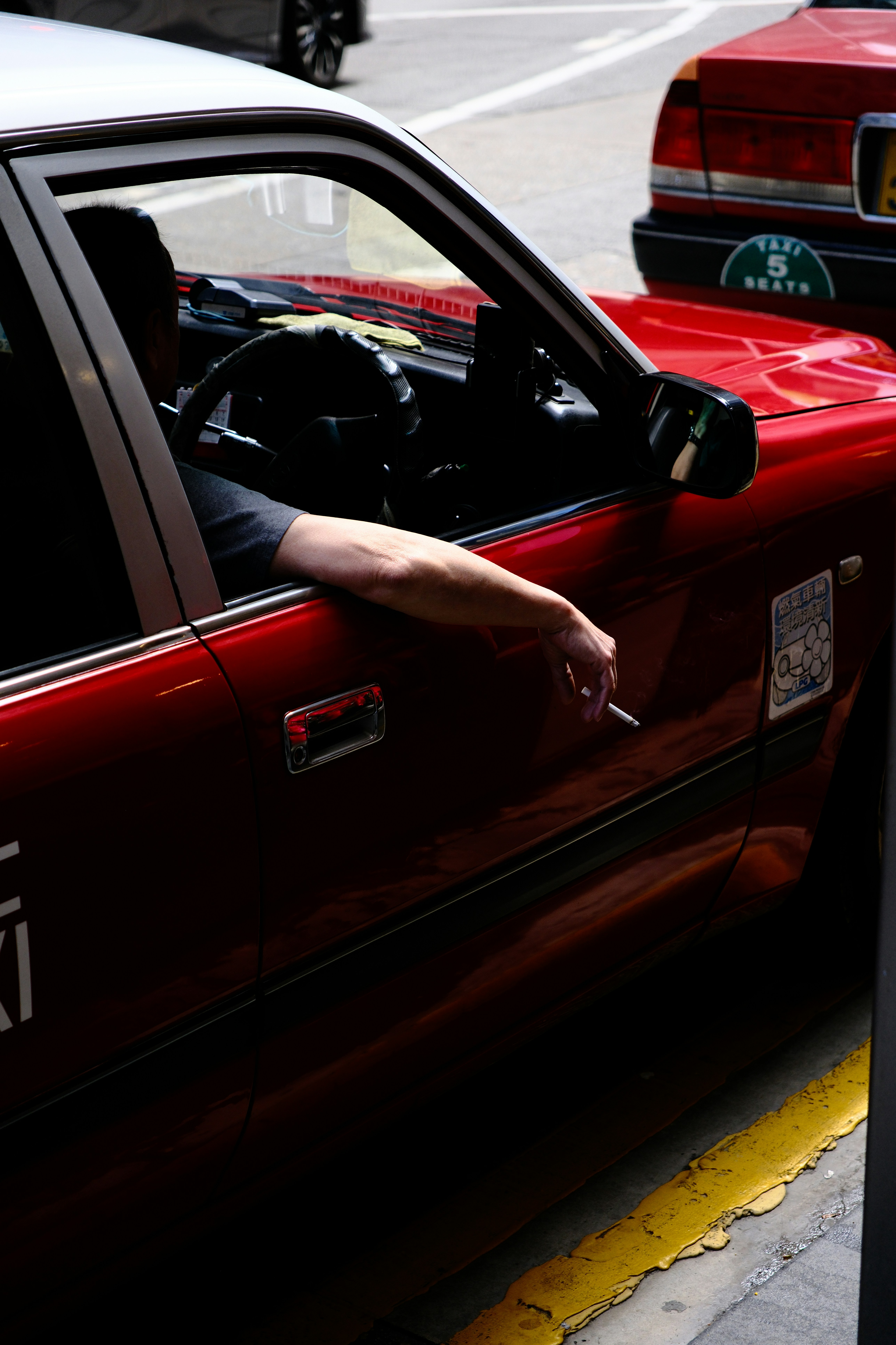 Red Cab Window: A Fist, a Smoke, and the Streetlight Quietly at Dusk