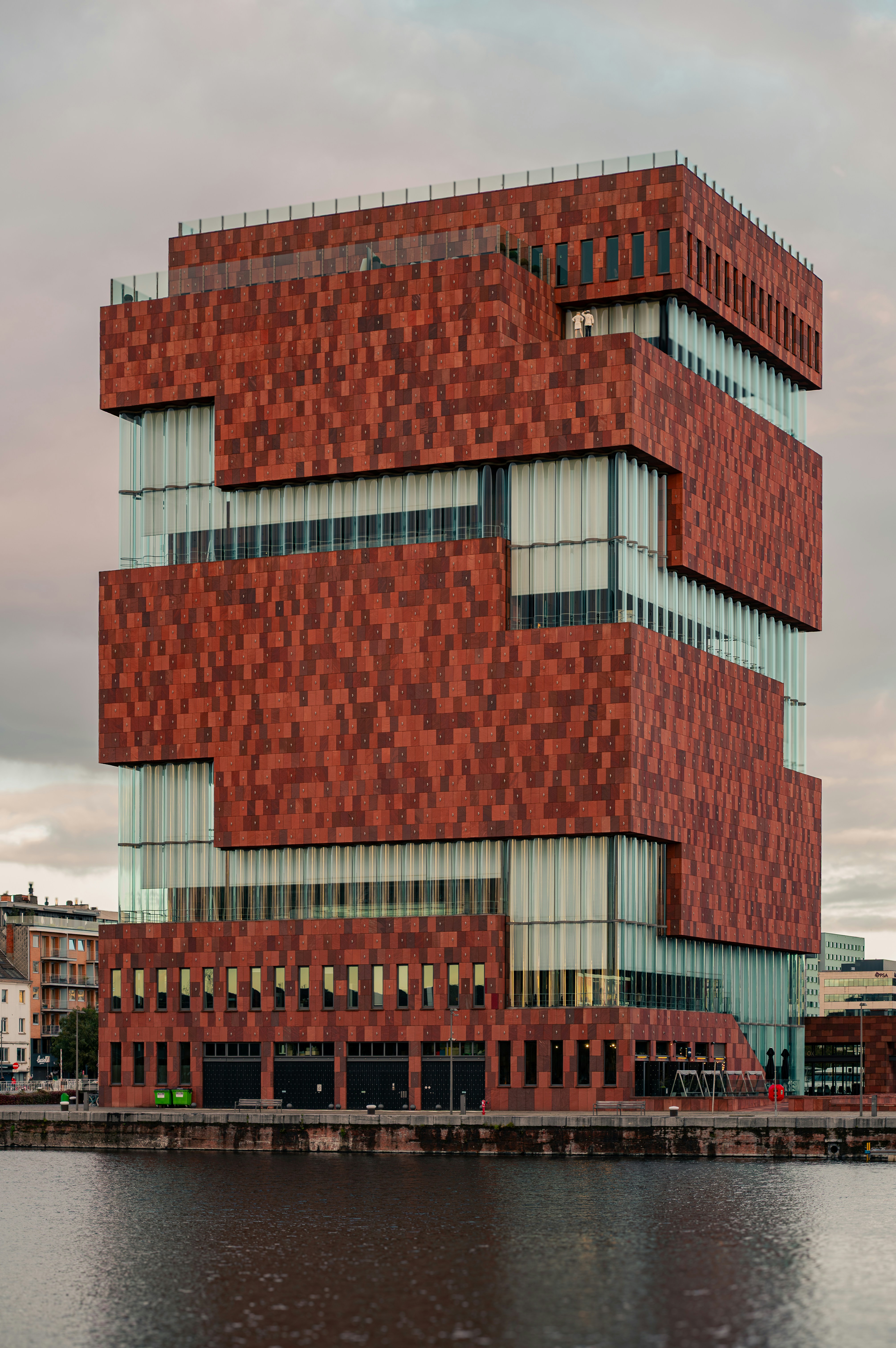 Red-blocked architectural sculpture rising from the river edge