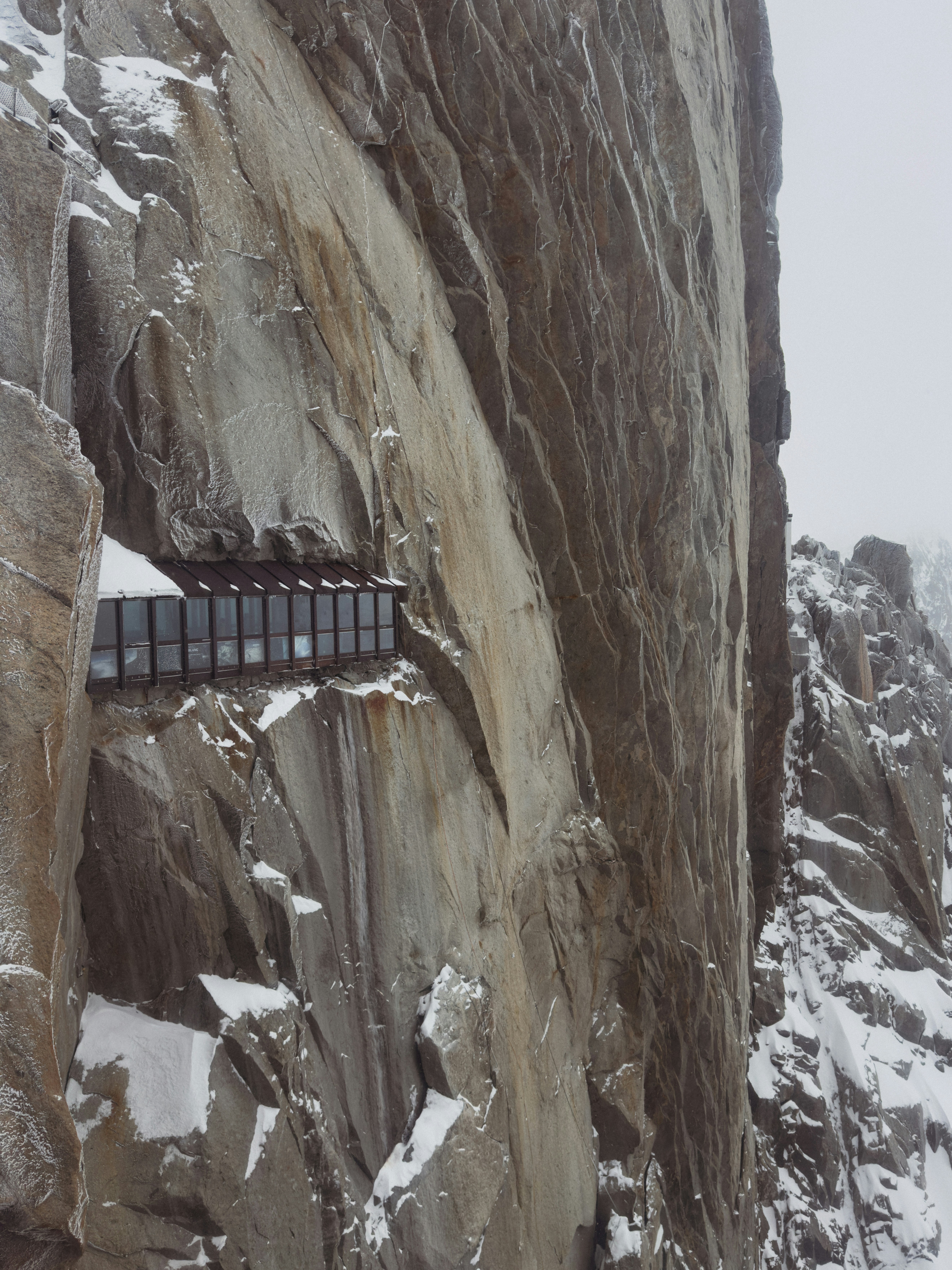 Cliffside Window: Snow-Capped Ridge and Metal Vista
