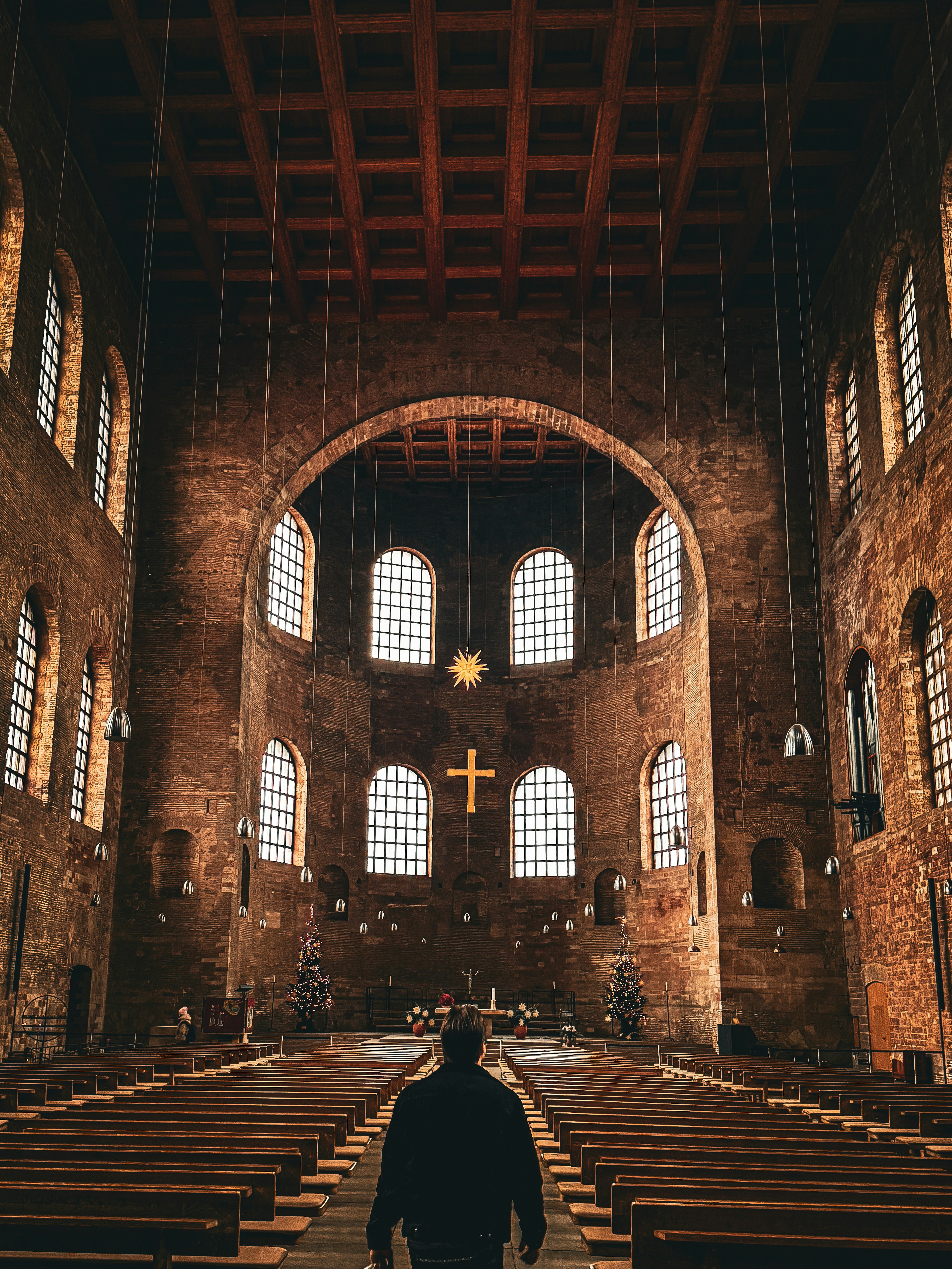 Cathedral of Quiet Resolve: A lone visitor before the cruciform window