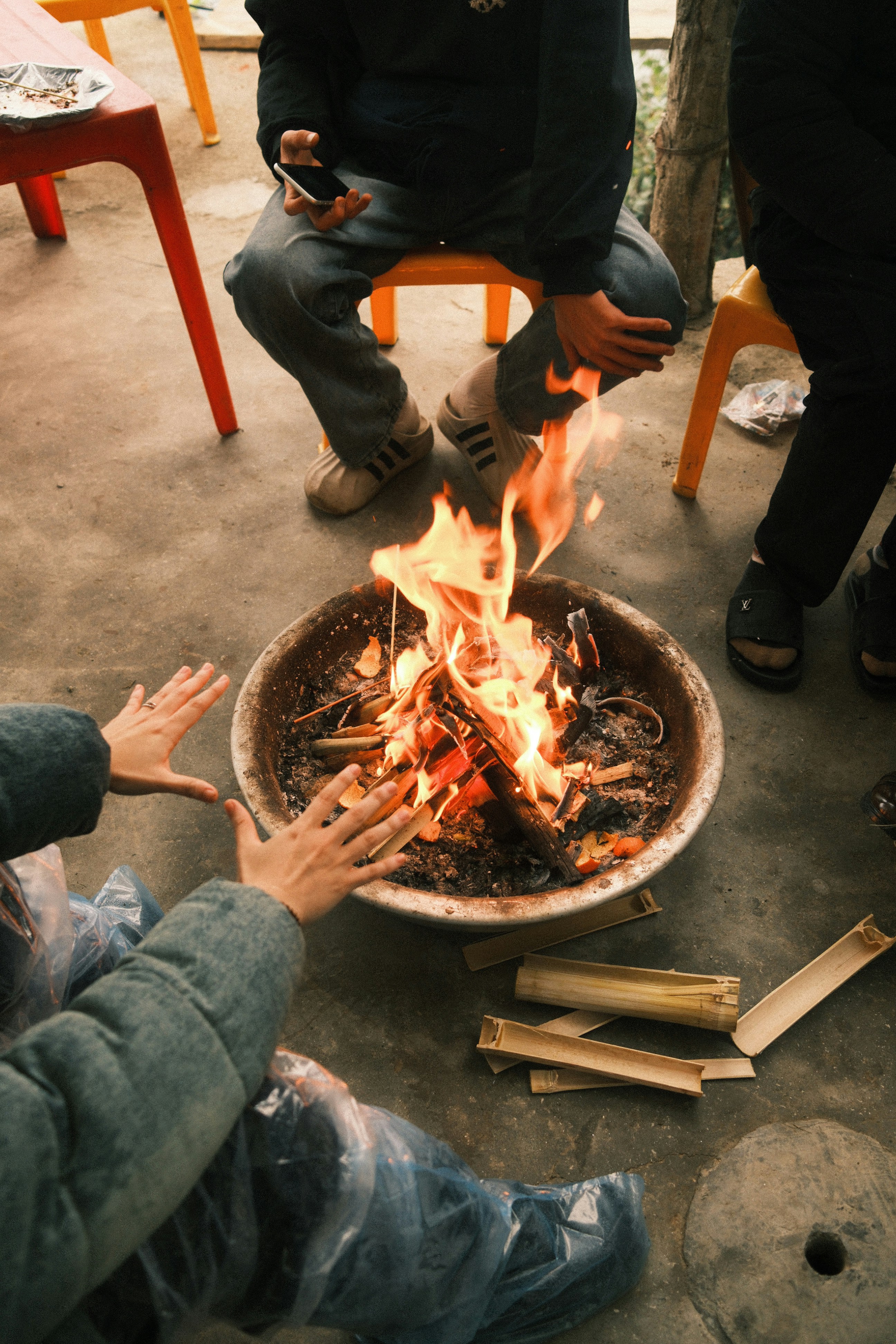 Firelight Moments: Hands Warm the Basin as Friends Gather