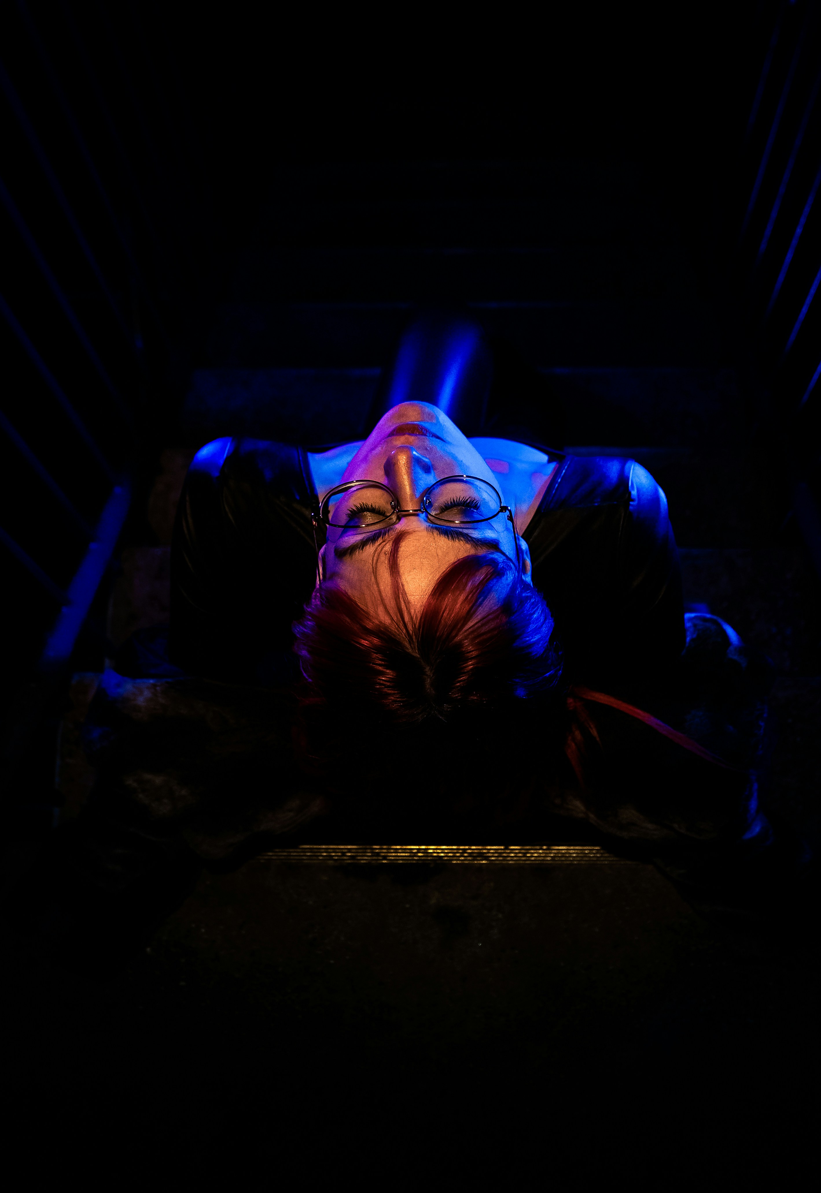 Eyes in Neon: Glasses Glow on a Face in the Dark Stairwell
