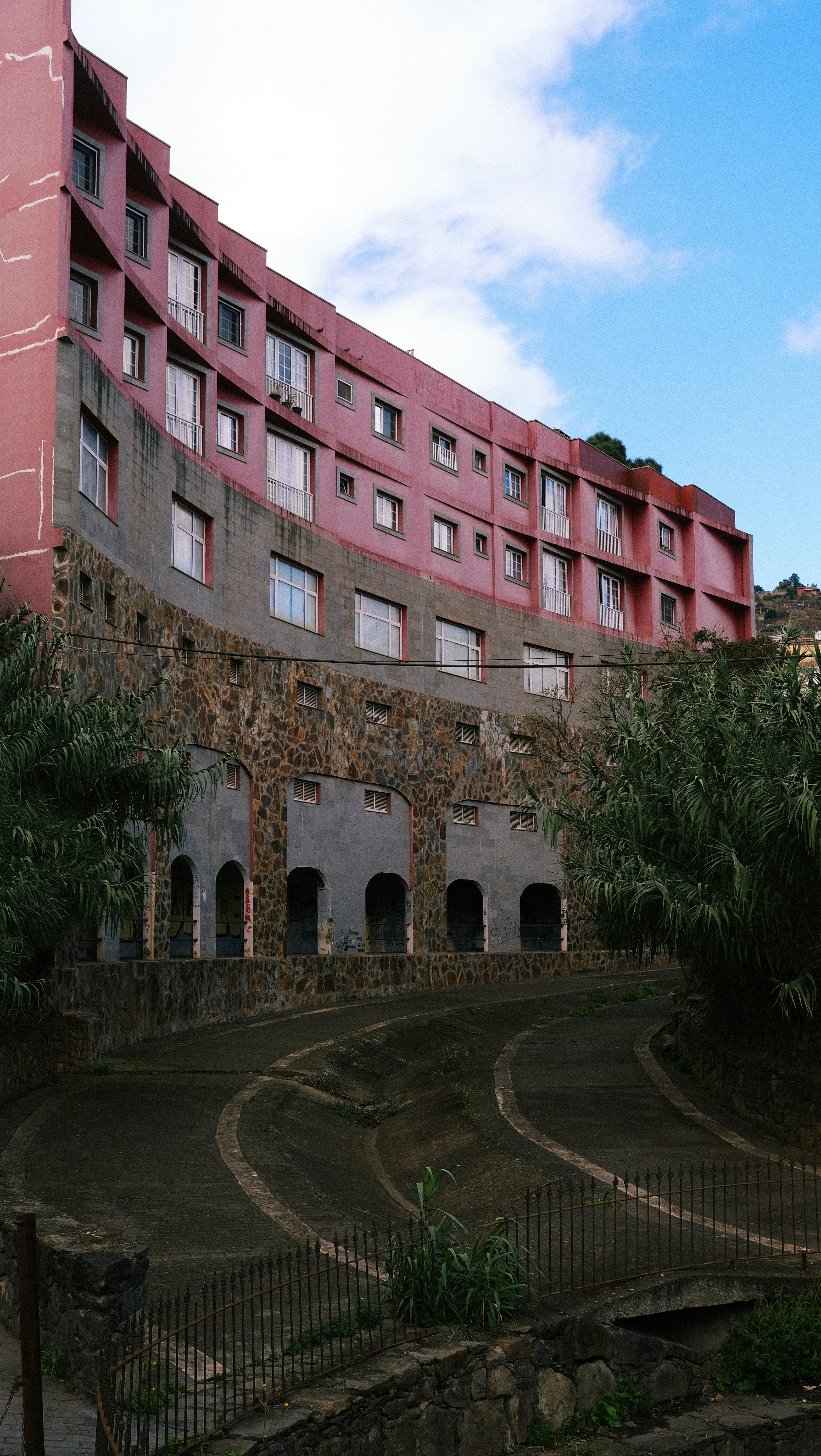Curved Pink Facade: A Winding Path Beneath a Slate Sky