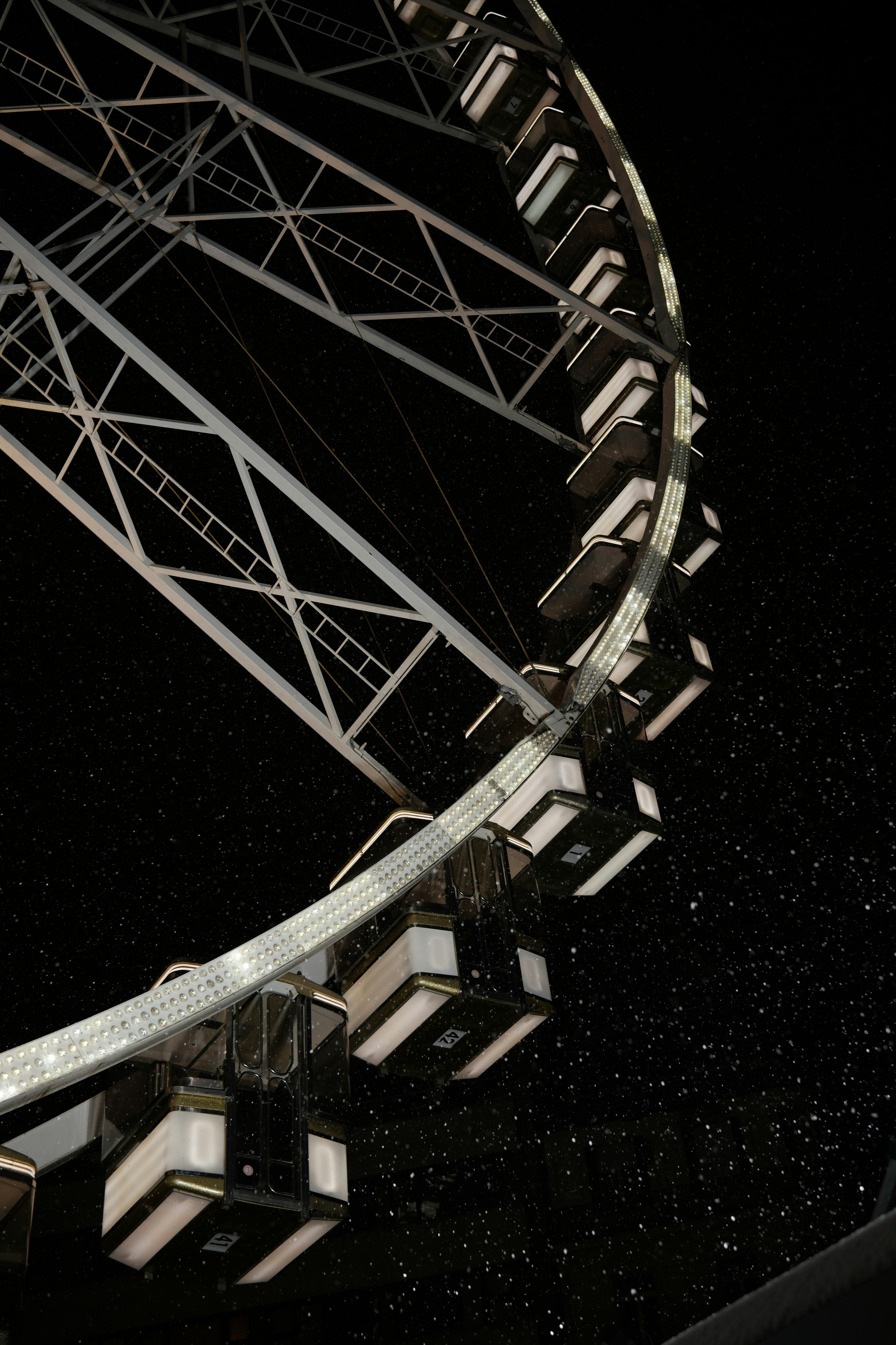 Night ride on the spinning wheel: a close glimpse of the Edinburgh-like Ferris structure against a starry backdrop