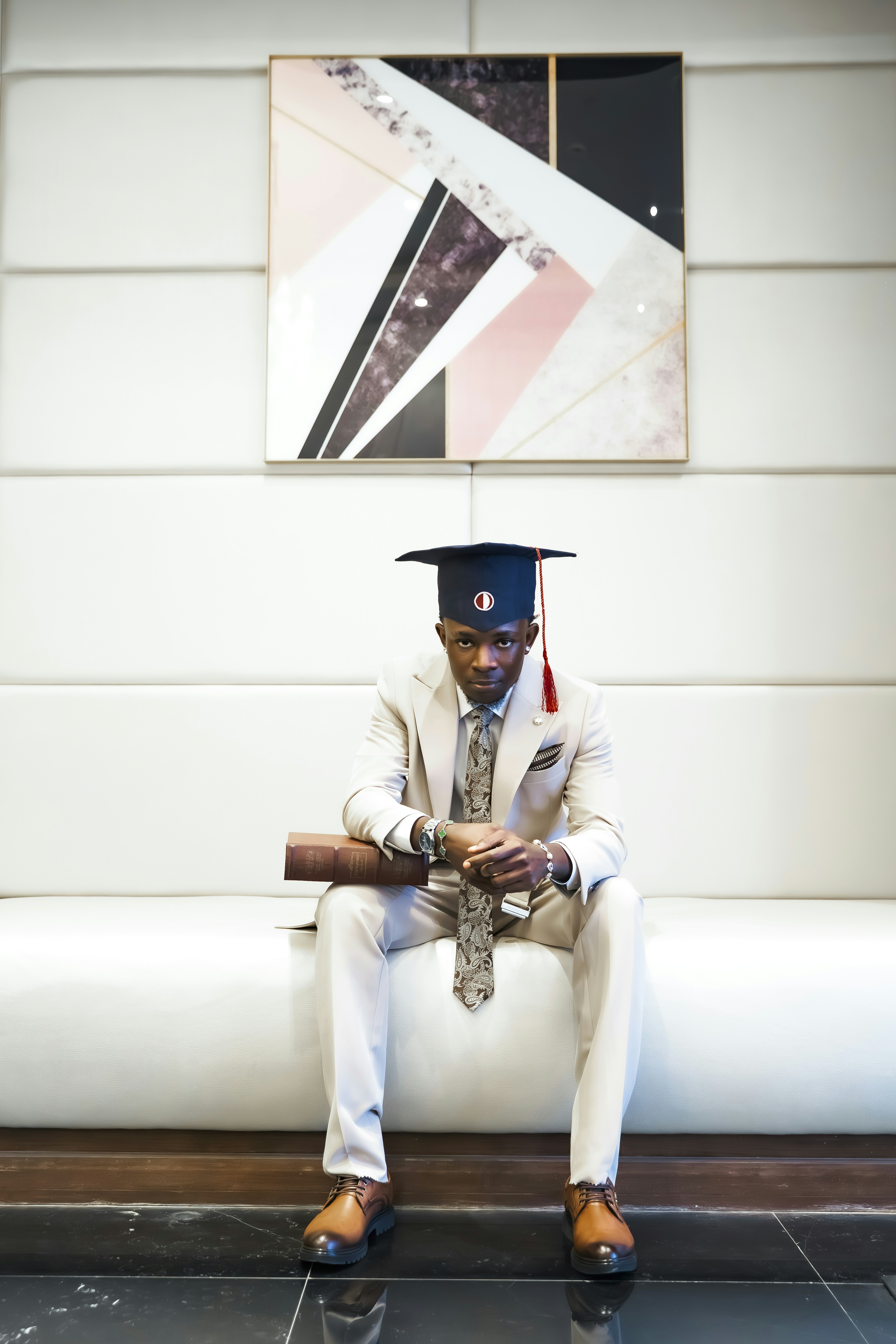 Seated graduate in crisp beige suit awaiting the next chapter