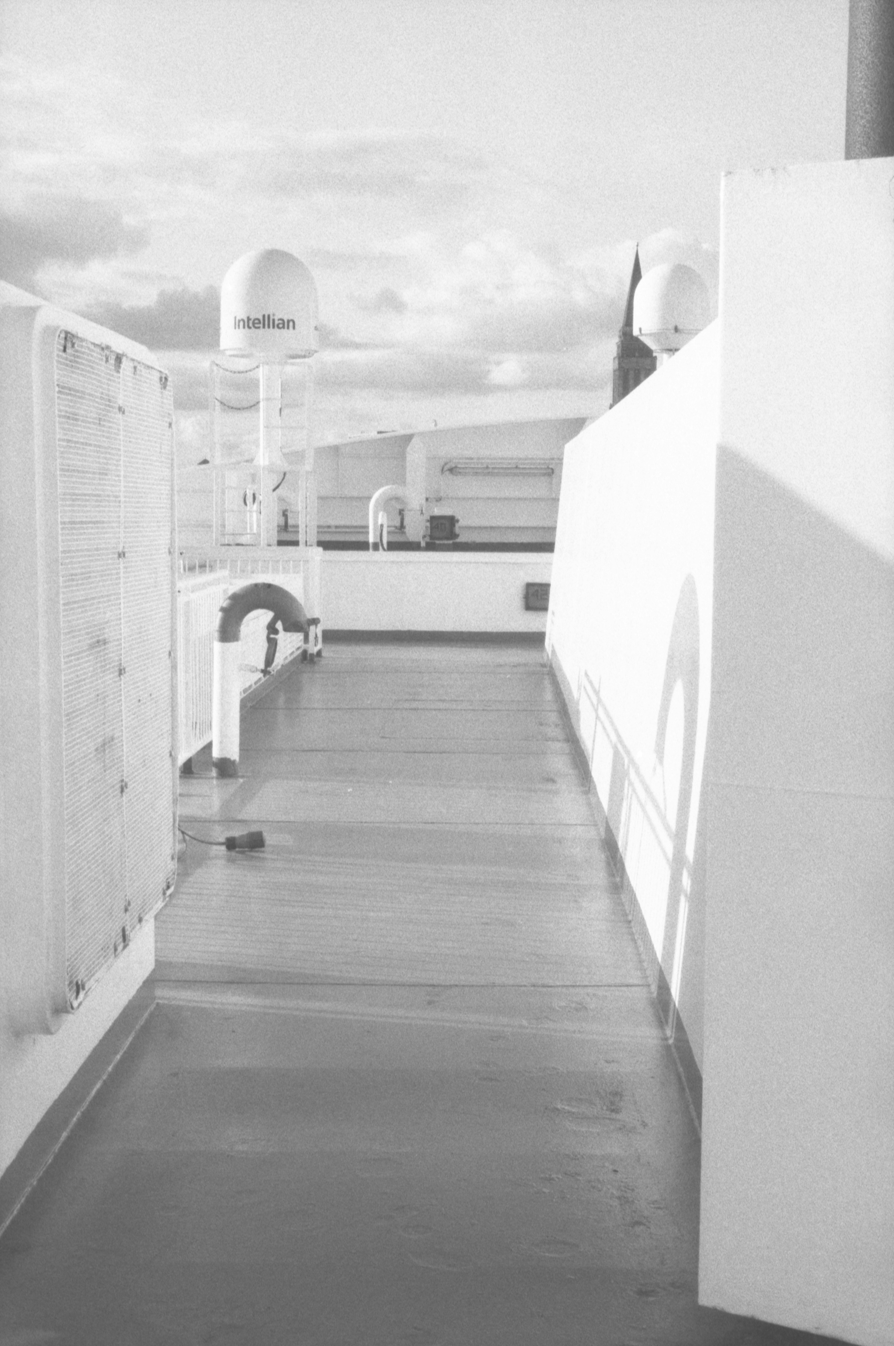 Deck of a ship with white railings and cloudy sky