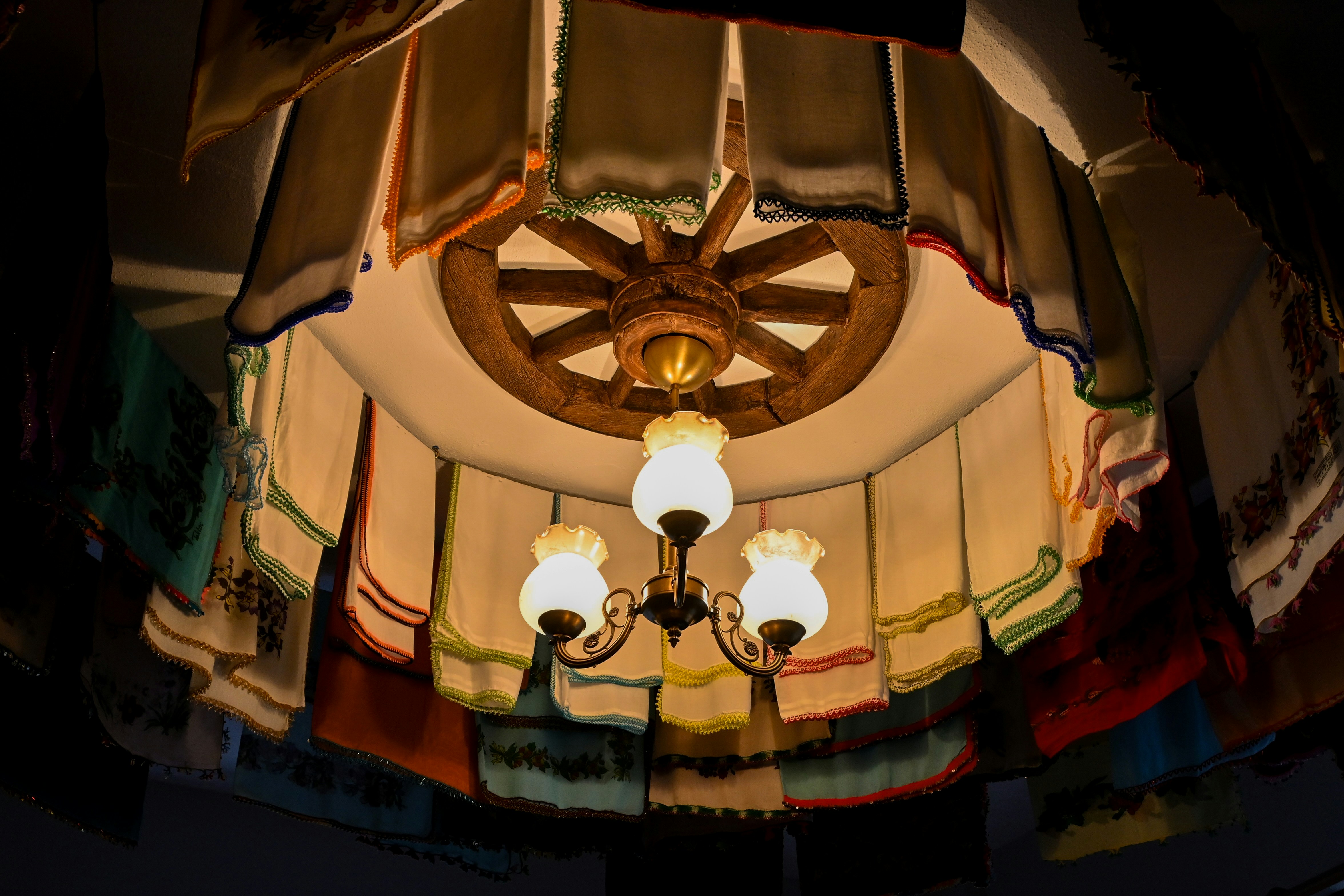 Chandelier Carousel: A Whirl of Fabric Flags Under Warm Glass Light