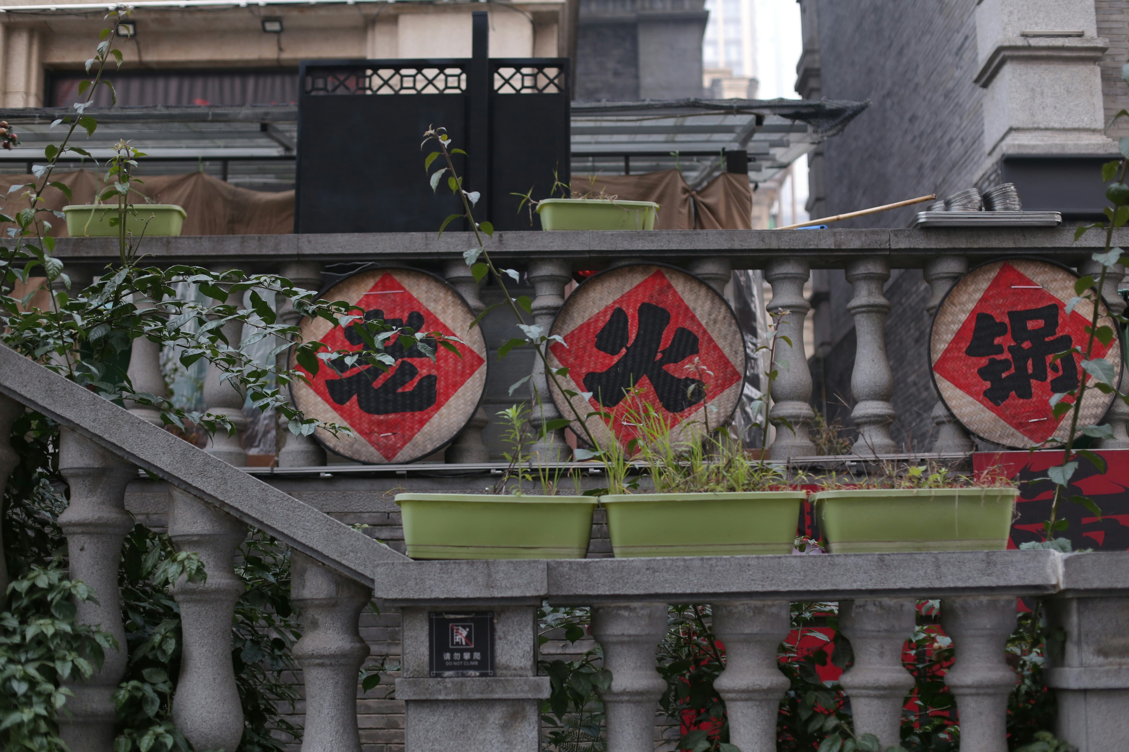 Red Lanterns on a Concrete Terrace Guarded by Green Planters