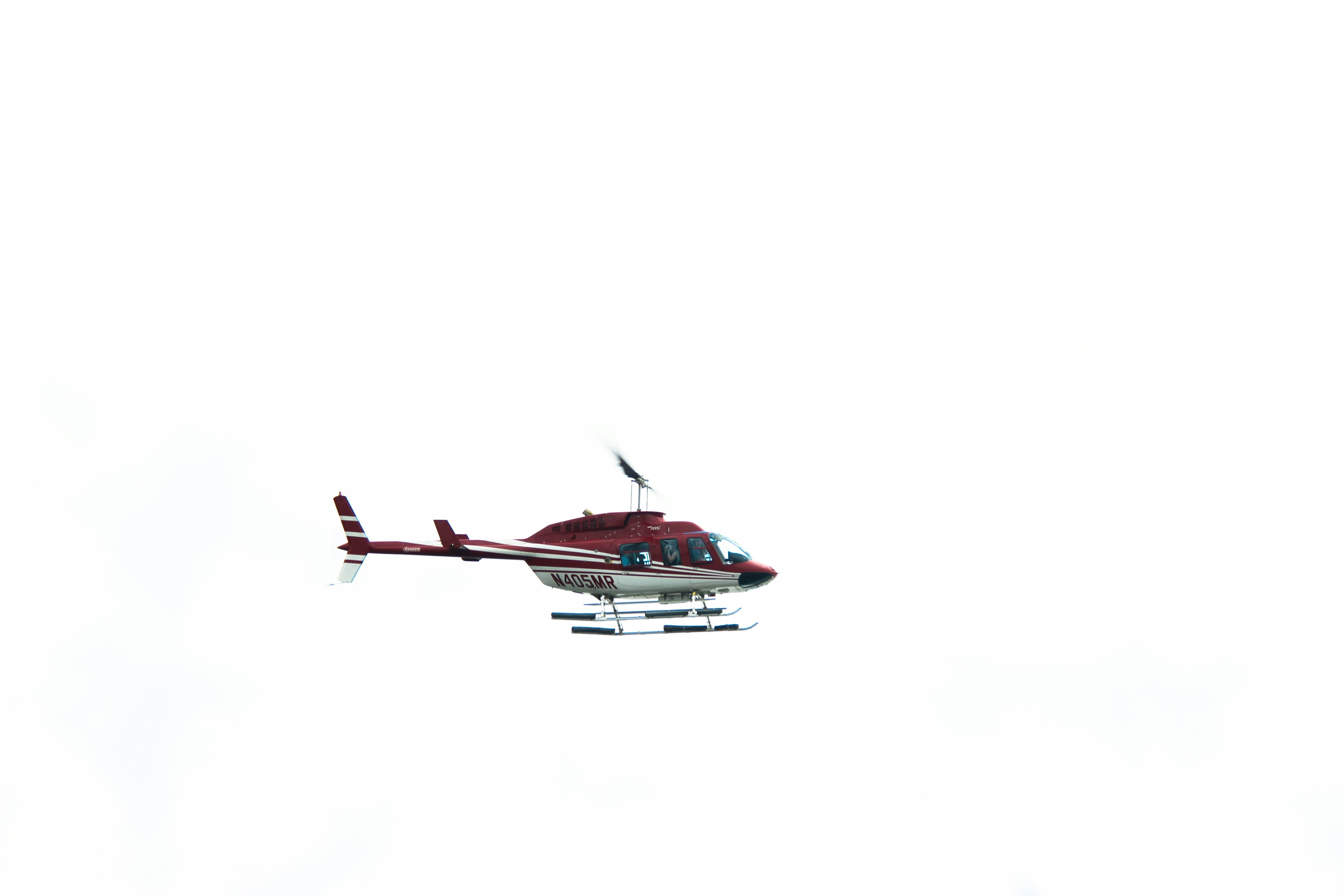 Red chopper in pale sky: midflight over calm frame
