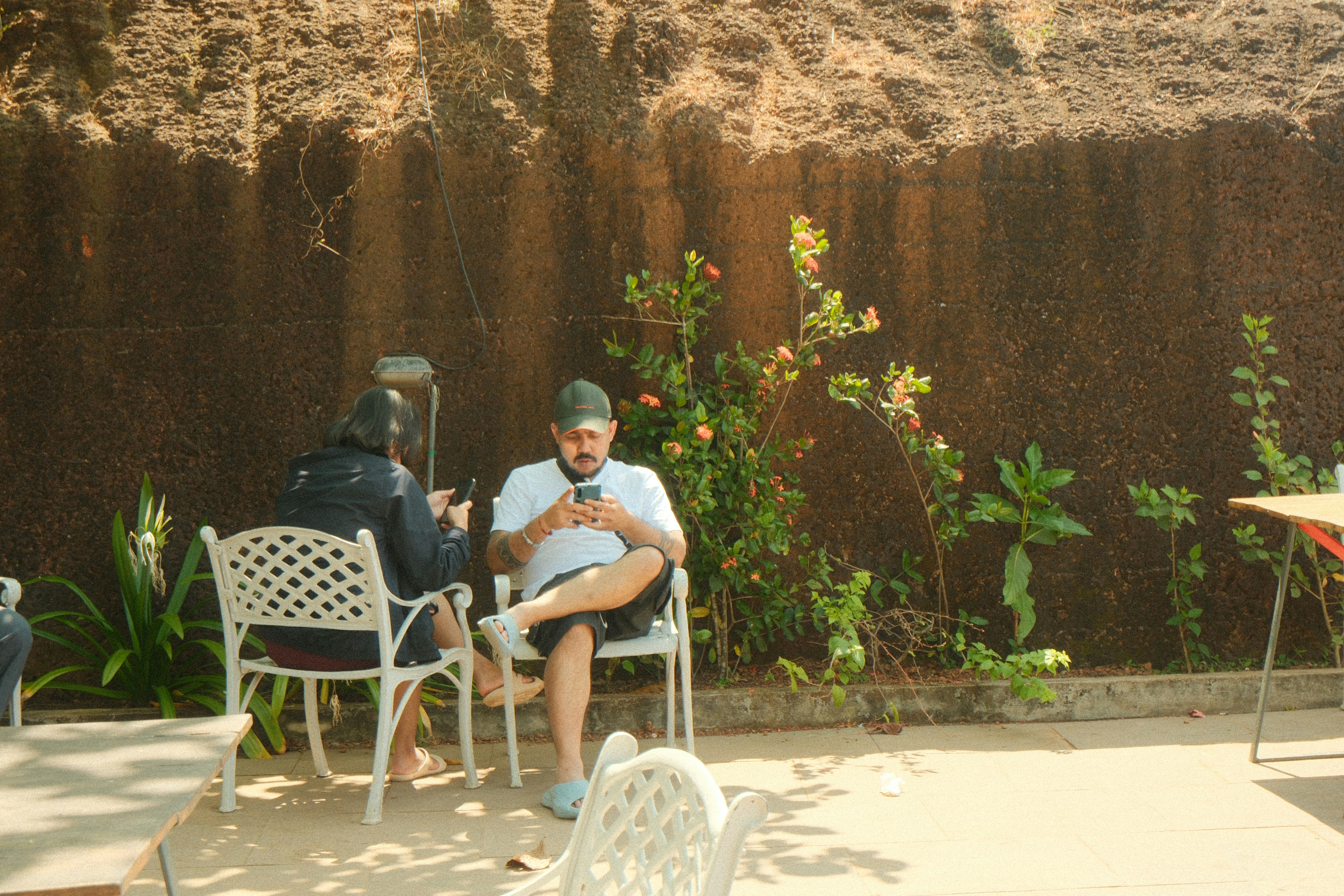 Paused Conversation: Two Men in Shade with Mobile Snippet