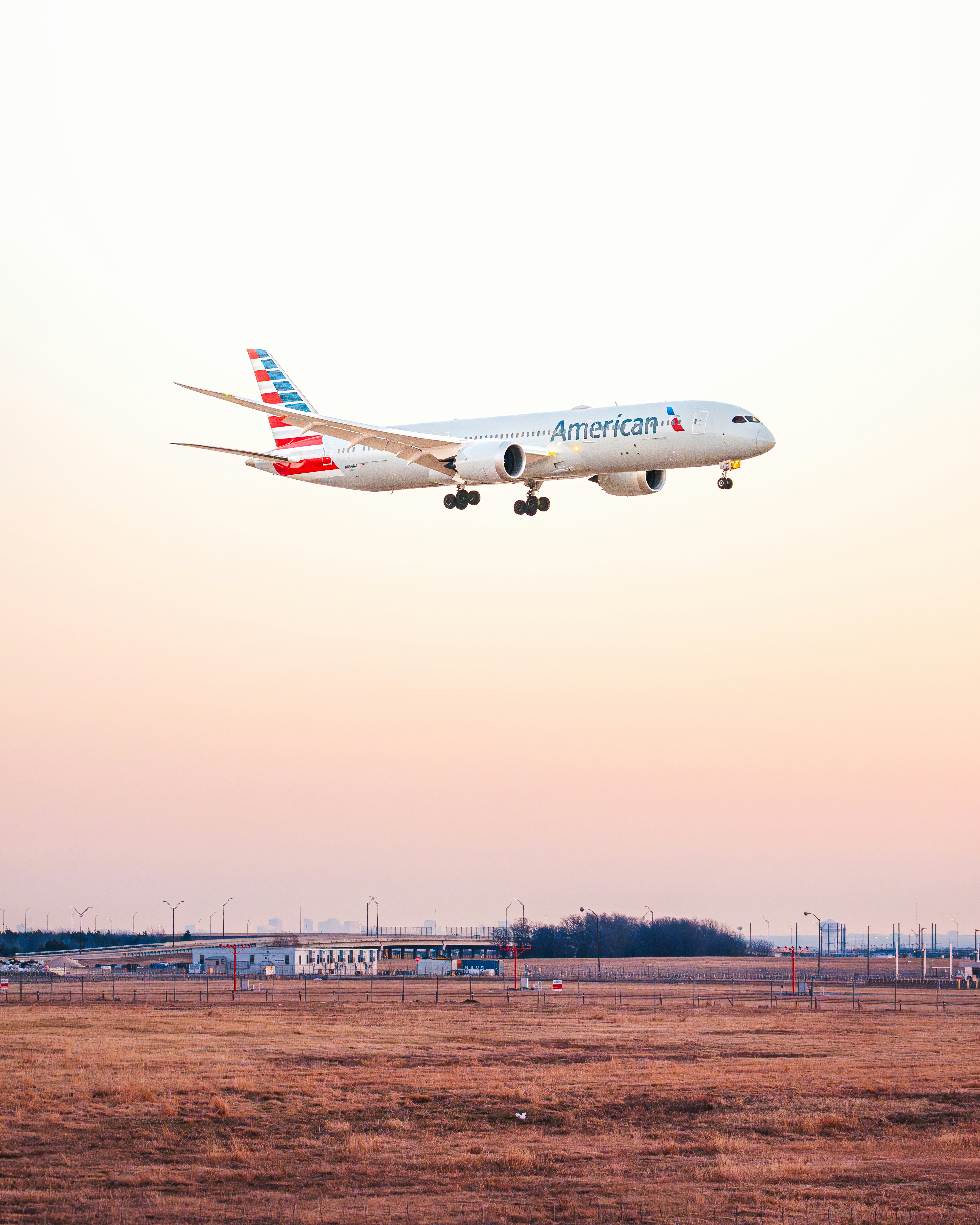 Approach over the flat horizon: American Airlines jet glides in at sunset