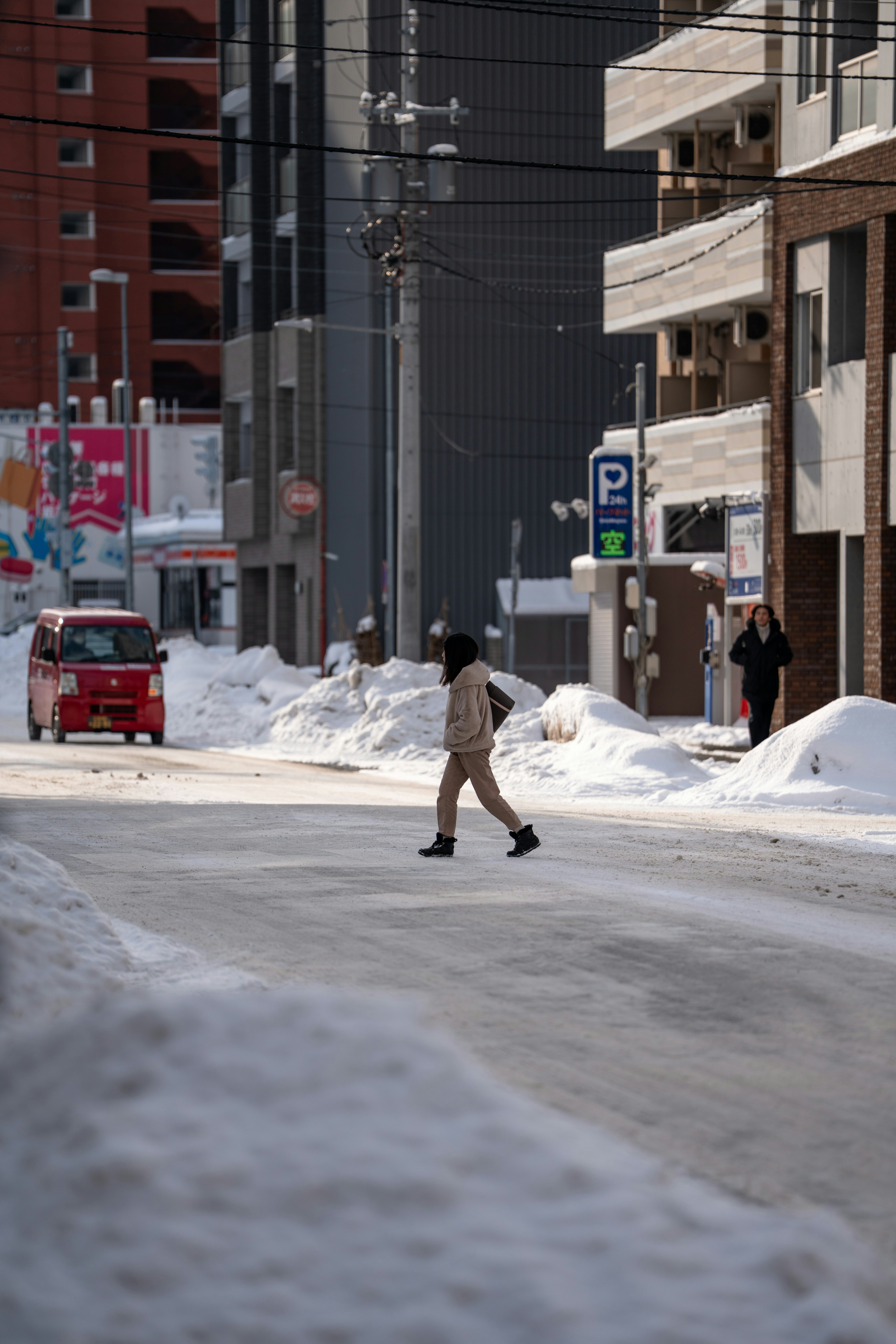 Crosswalk in Winter: A Lone Pedestrian Traverses a Snow-Scarred Street