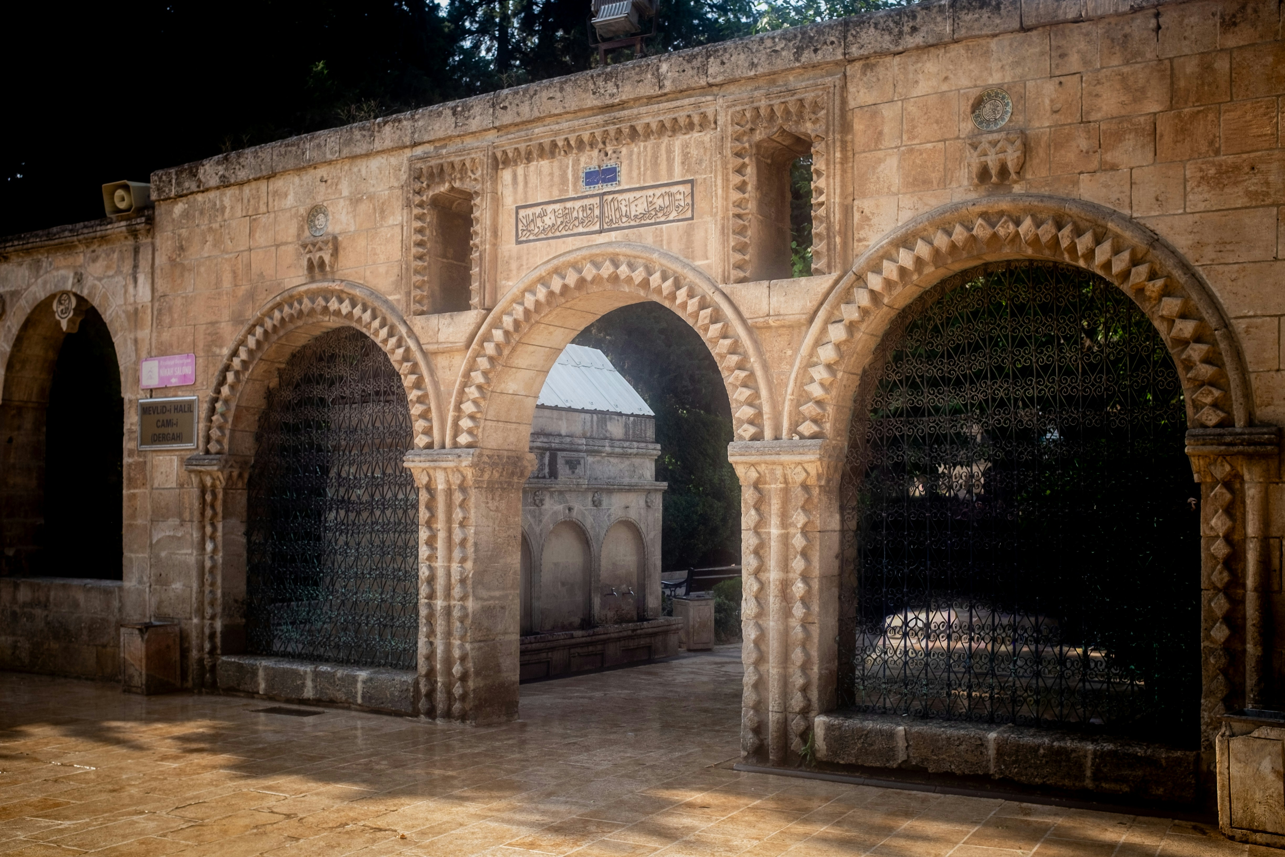 Arched Gatehouse in Warm Stone: Sunlit Courtyard Beneath Intricate Carvings