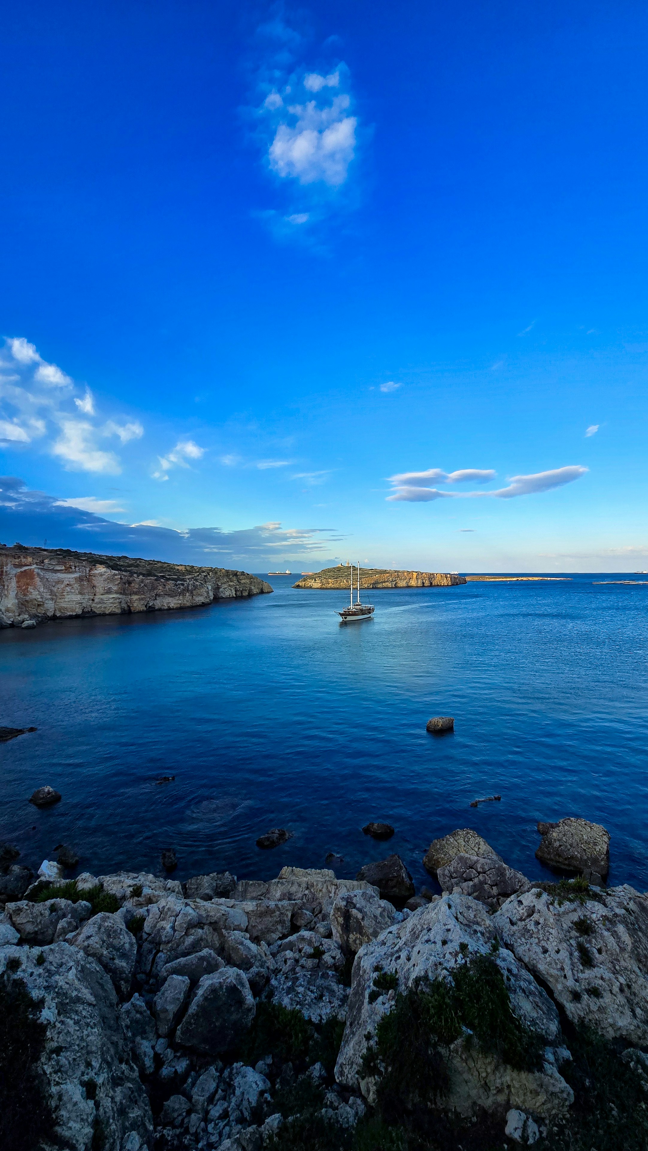 Coastal Rockscape with Sailboat under Slipstream Sky