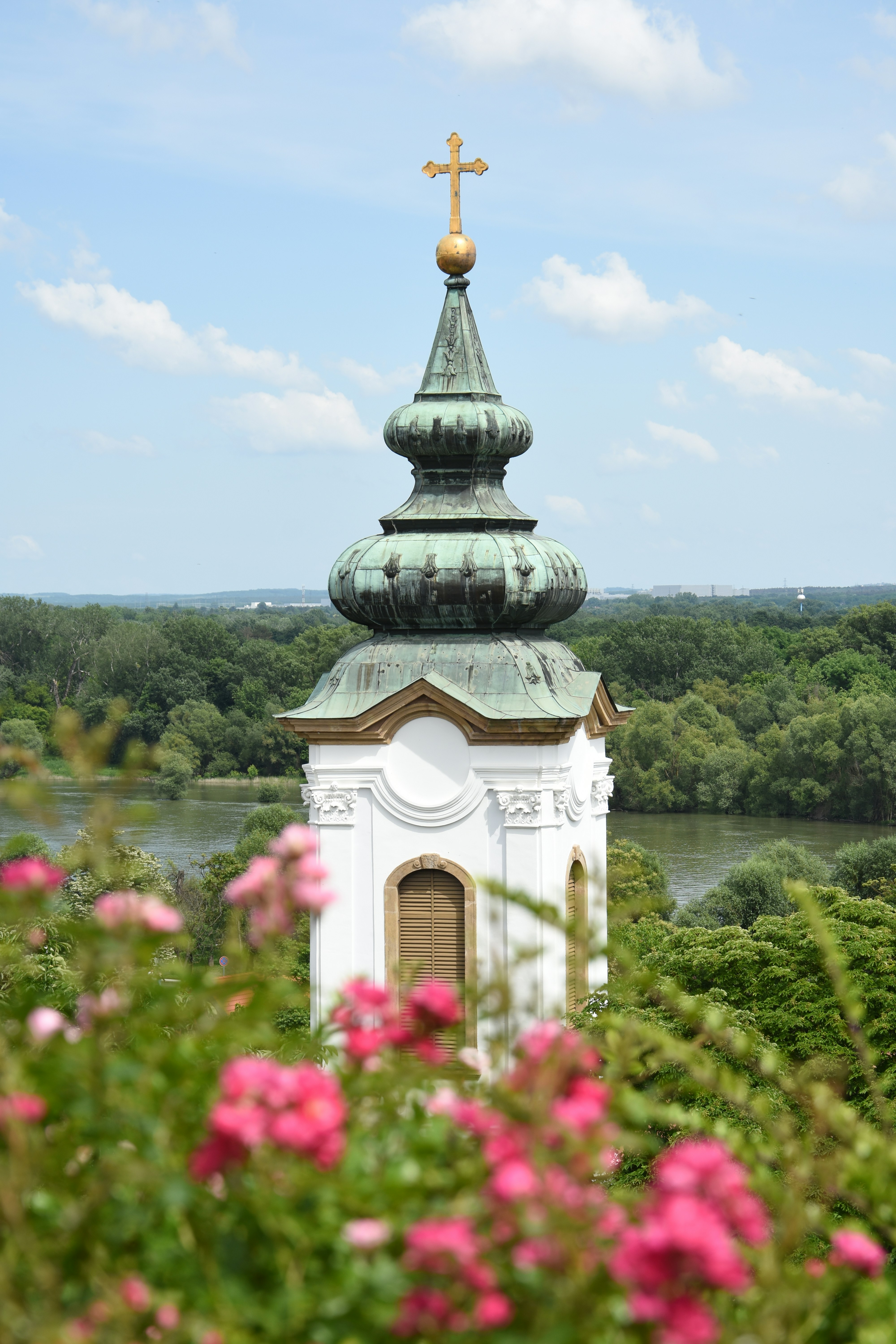 A WWI-era chapel spire rises above a river bend framed by blossoms