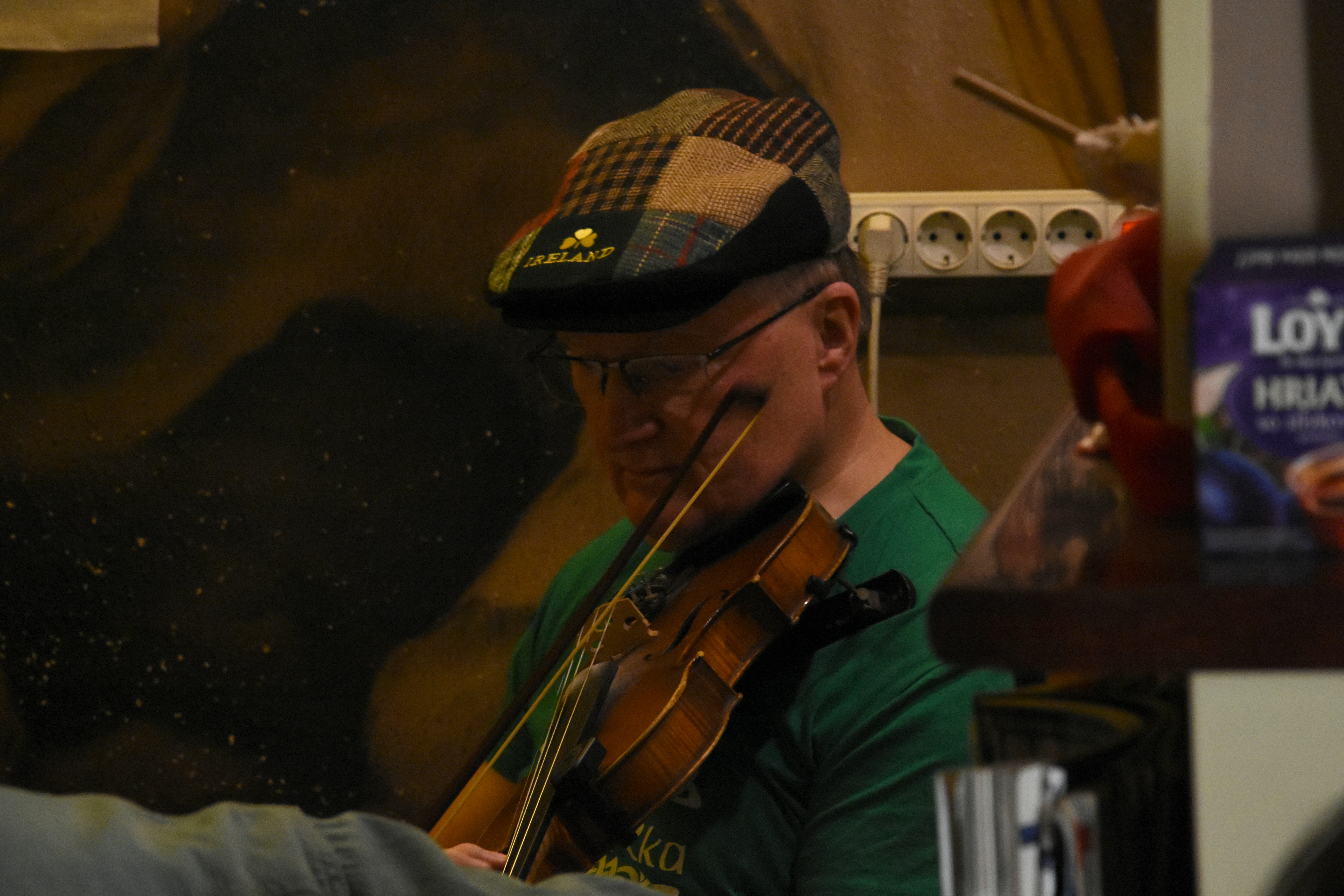 A violinist in a cozy room playing under warm light